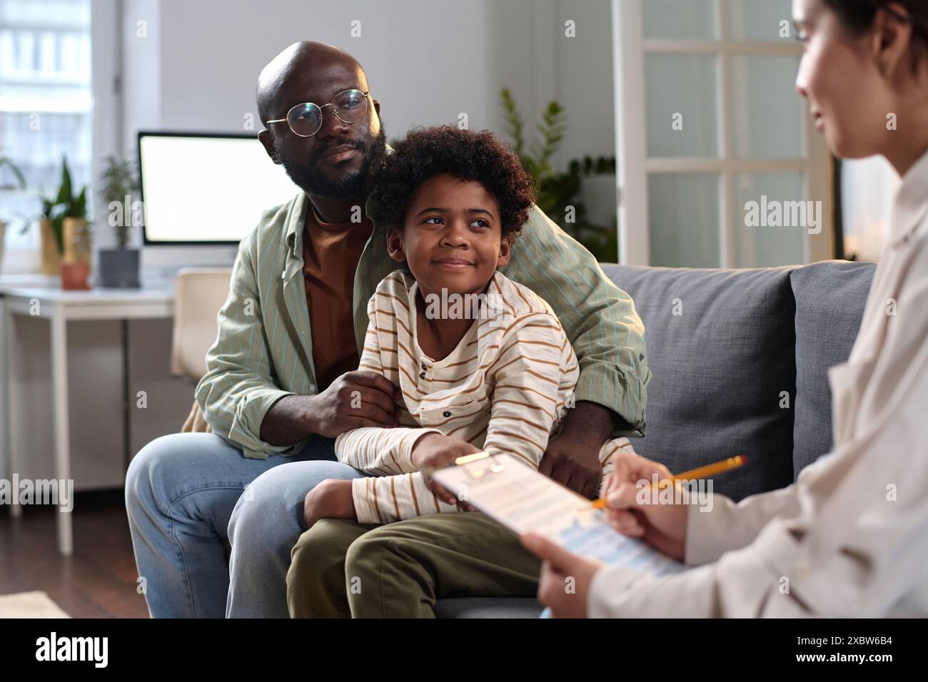 Portrait of smiling father and son listening to social worker in ...