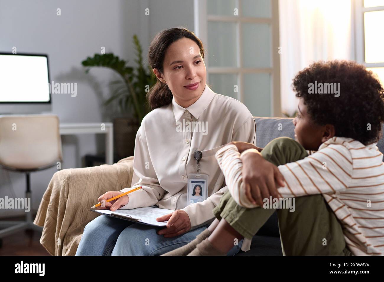 Portrait of female psychologist talking to young child in therapy ...