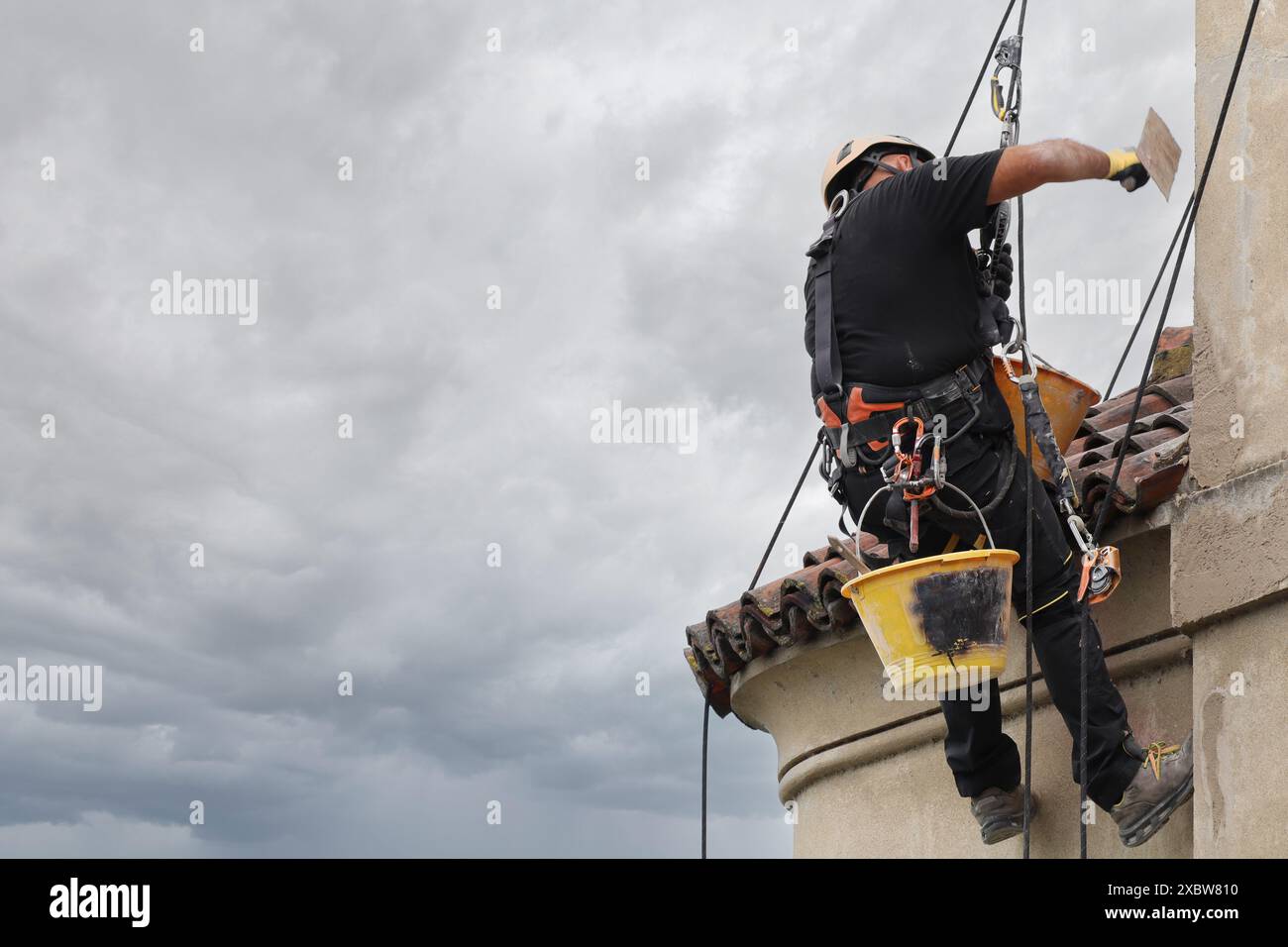 Acrobatic rope building employee standing in mid air working on a ...