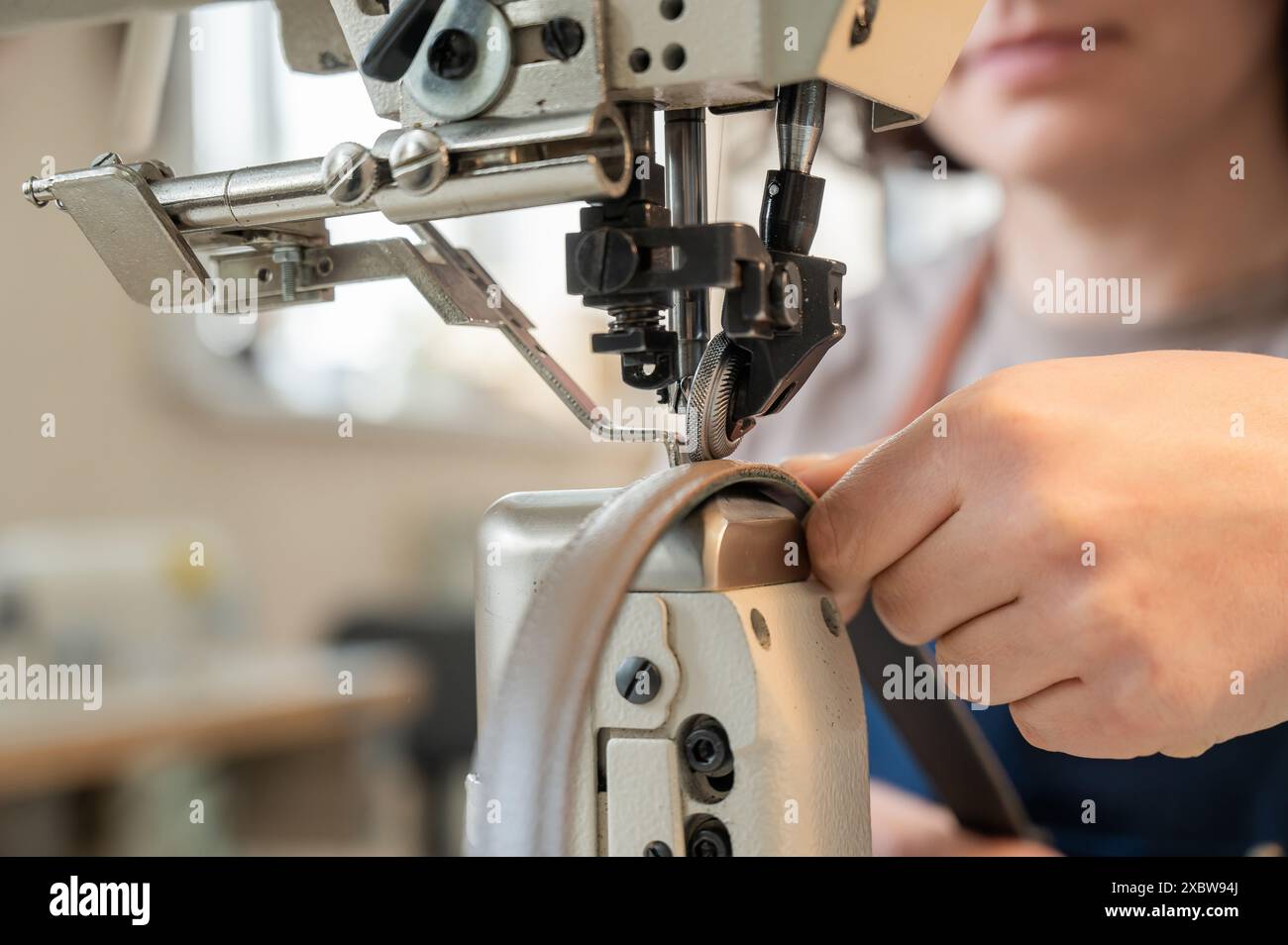 A woman tanner sews a leather belt on a sewing machine Stock Photo - Alamy