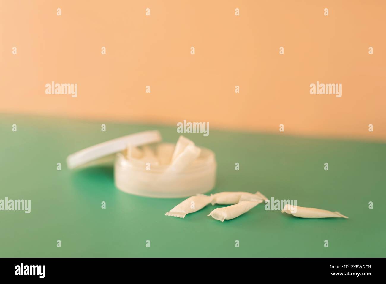 Plastic jar filled with white light snus sachets on a green background ...