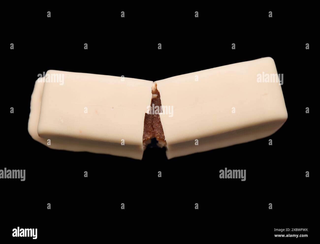 A split white chocolate bar reveals a luscious caramel center against a ...