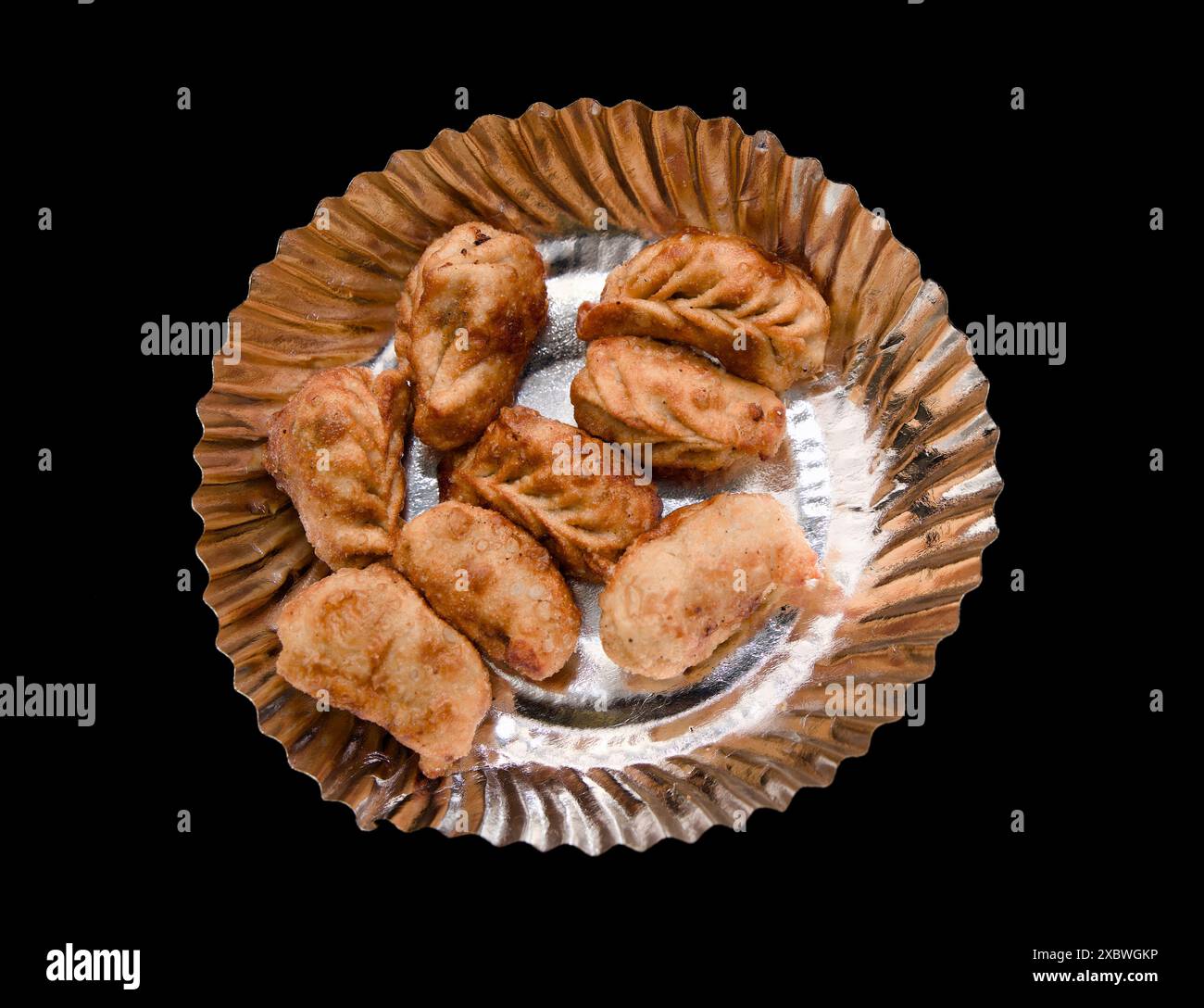 Delicious golden-brown fried momos arranged on a reflective plate ...