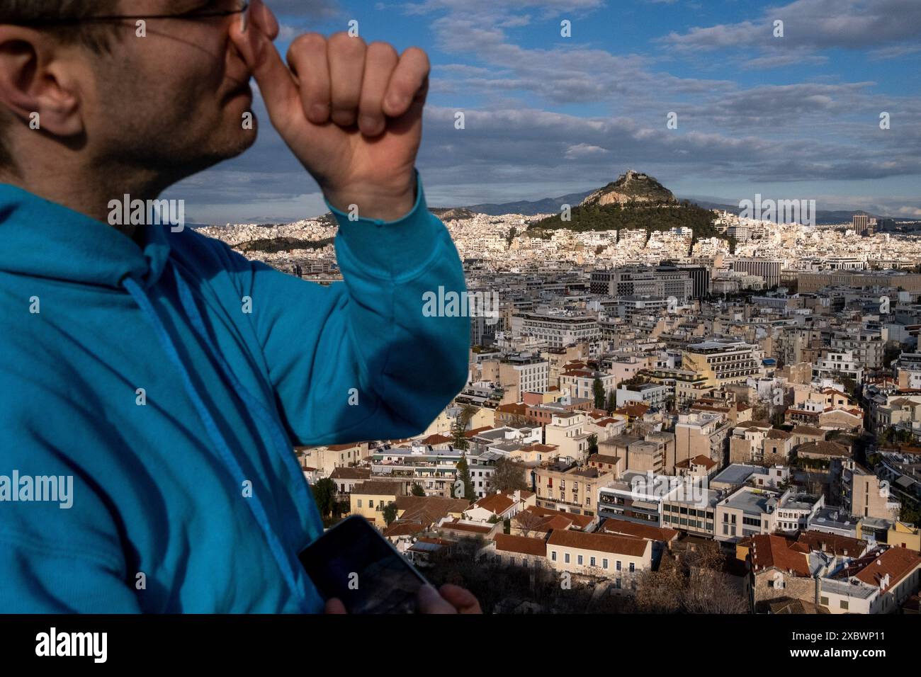 A tourist in the foreground of a view of Lycabettos Hill or Lykavittos ...