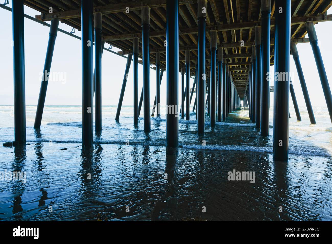 Under the pier. A long wooden pier, and ocean waves, a dramatic scene ...