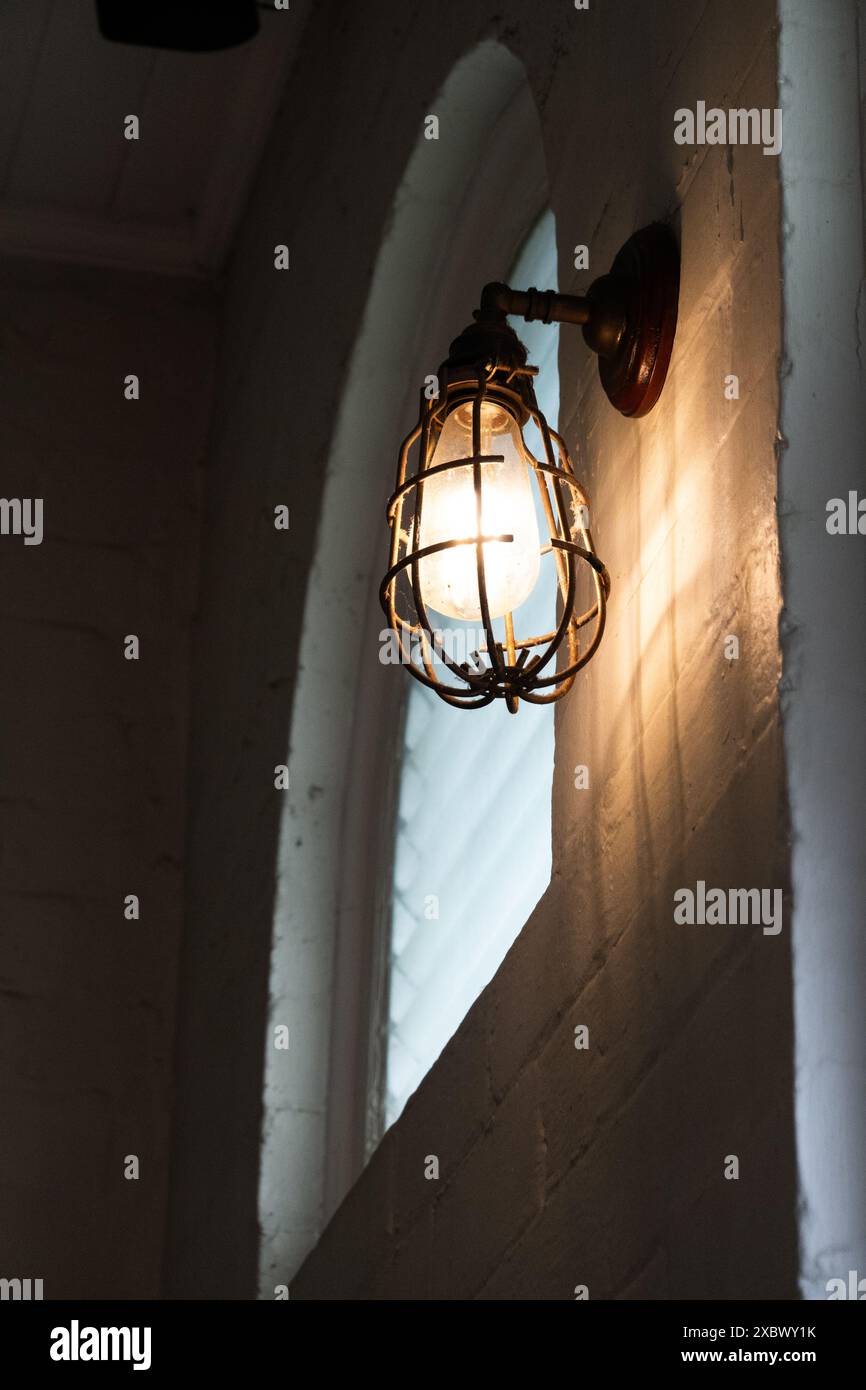 A vintage wall-mounted light fixture illuminating a brick wall next to ...