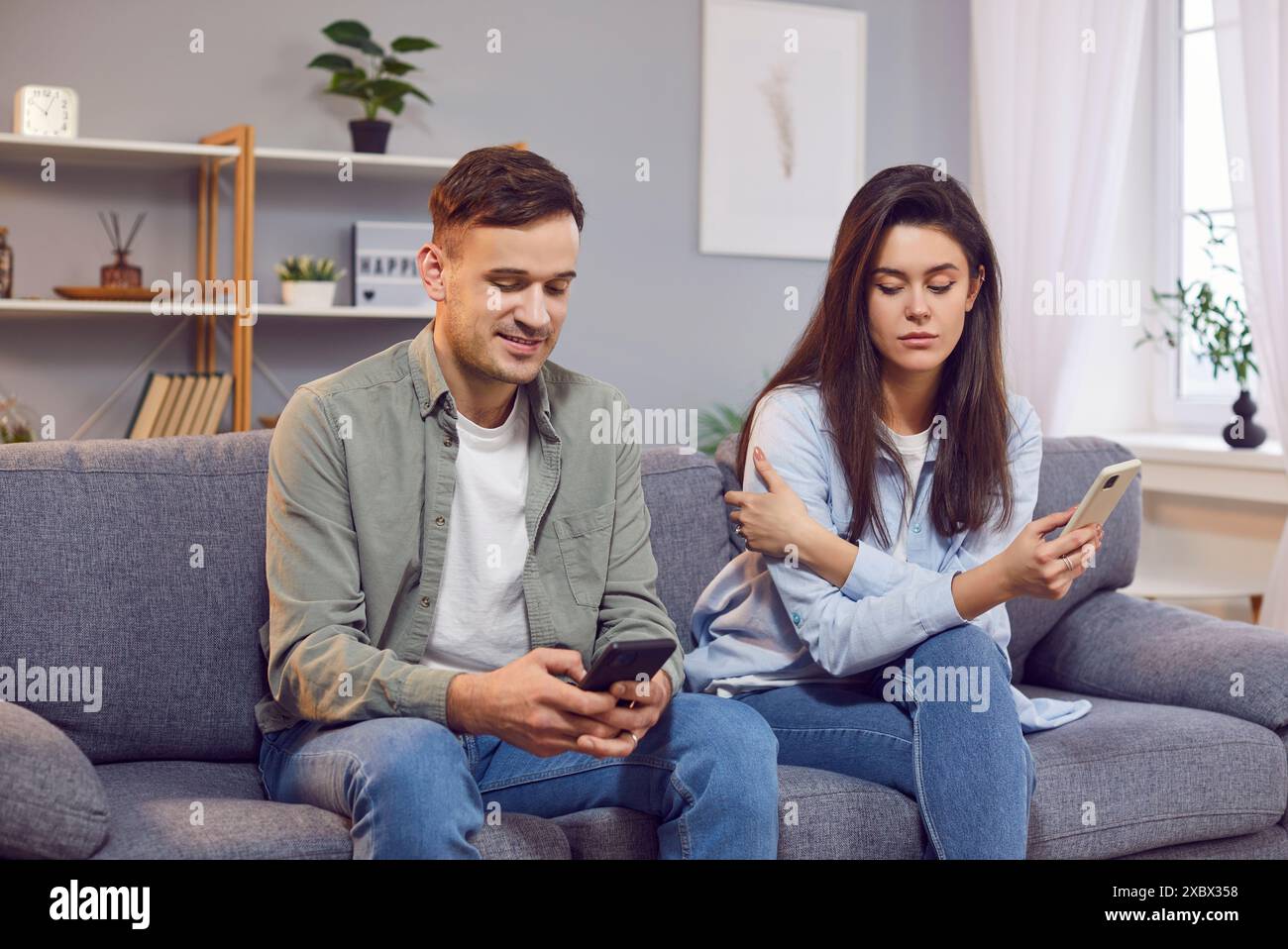 Woman secretly looks suspiciously at screen of man's smartphone, spying ...
