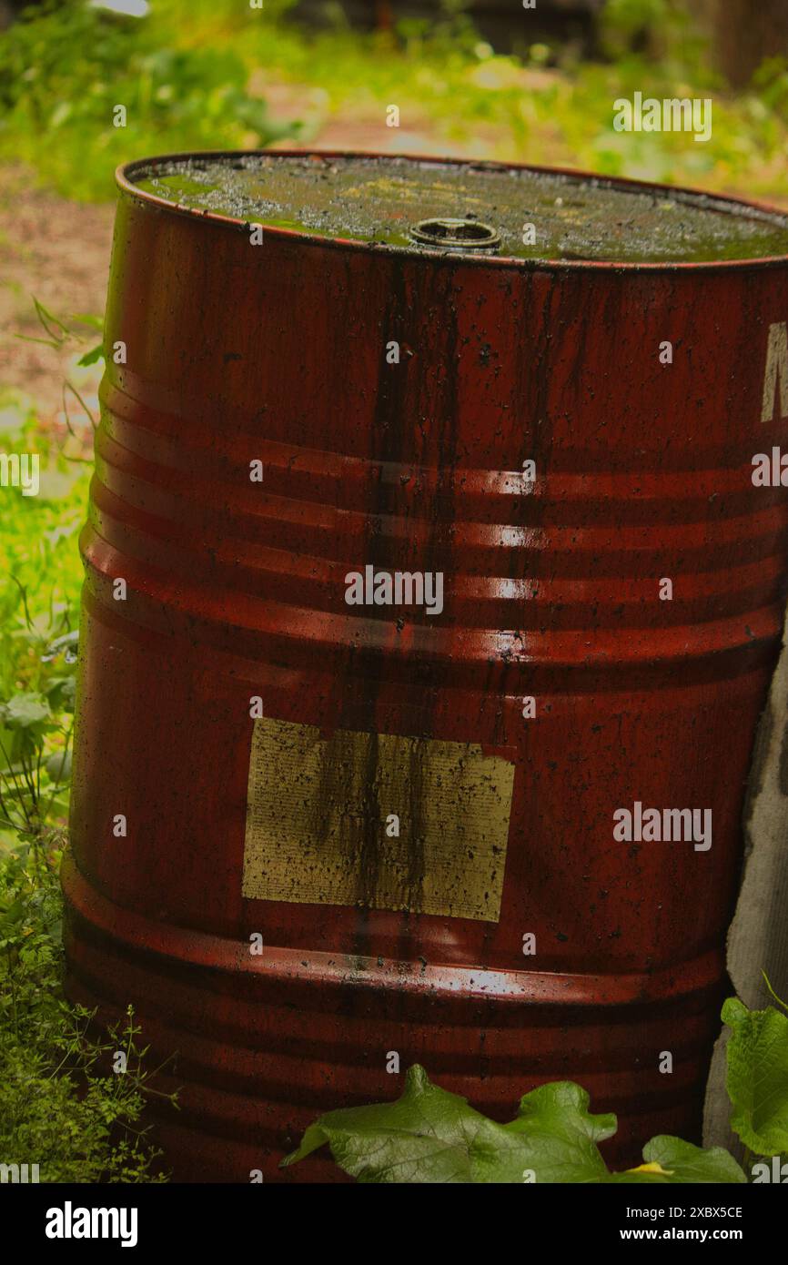 a metal red barrel stands on the street smeared with black liquid, dark ...