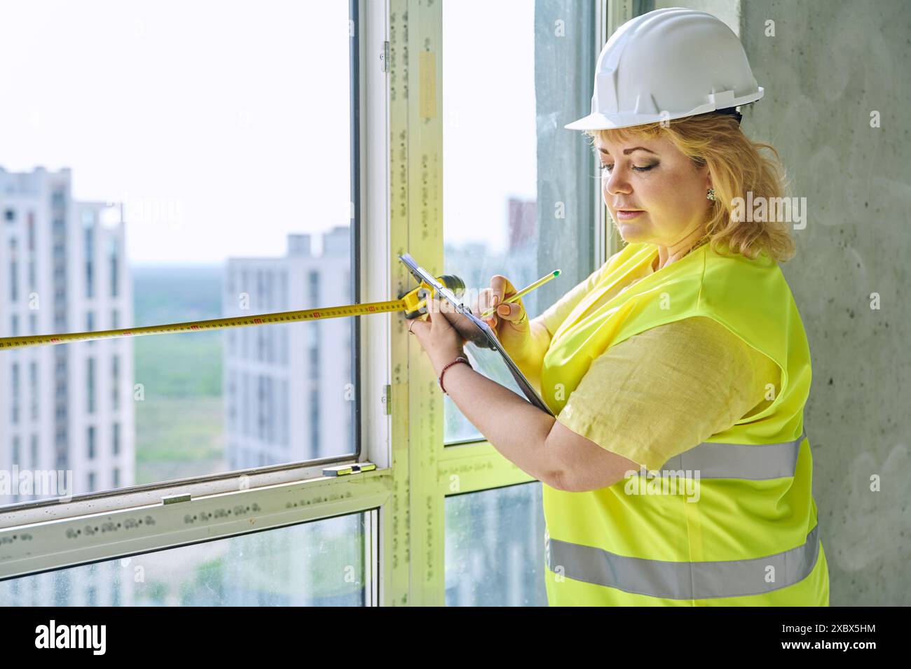 Female window decorator designer measuring window with tape measure ...