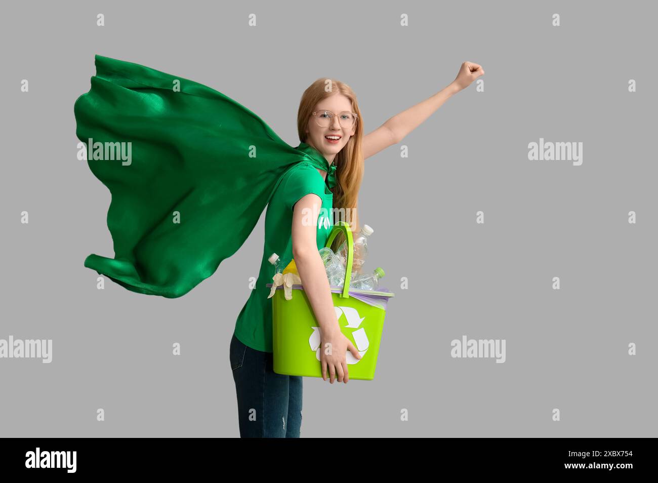 Female volunteer in superhero cape holding recycle bin with plastic on ...