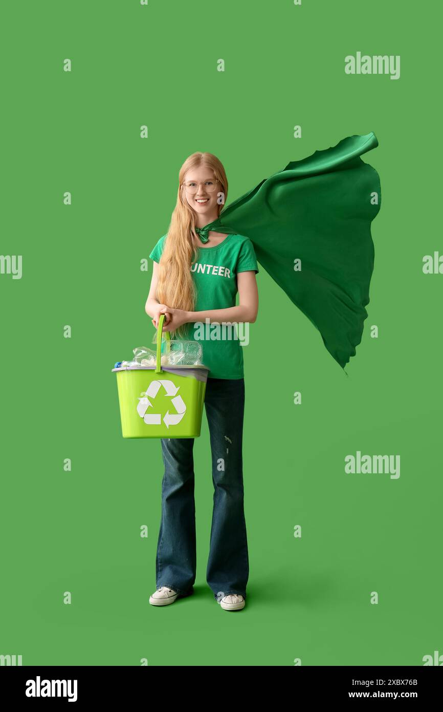 Female volunteer in superhero cape holding recycle bin with plastic on ...