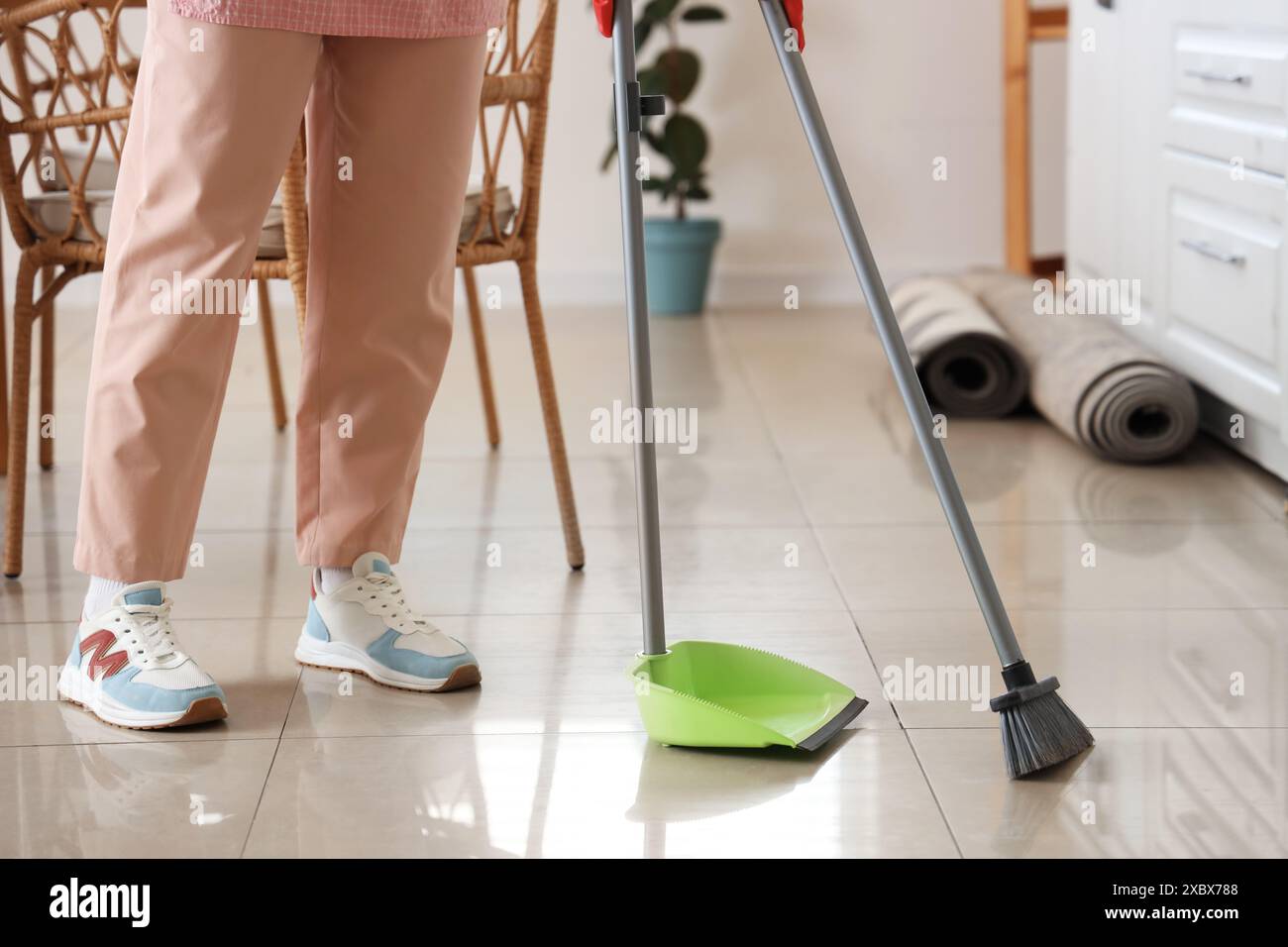 Woman sweeping tile floor with broom and dustpan at home Stock Photo ...