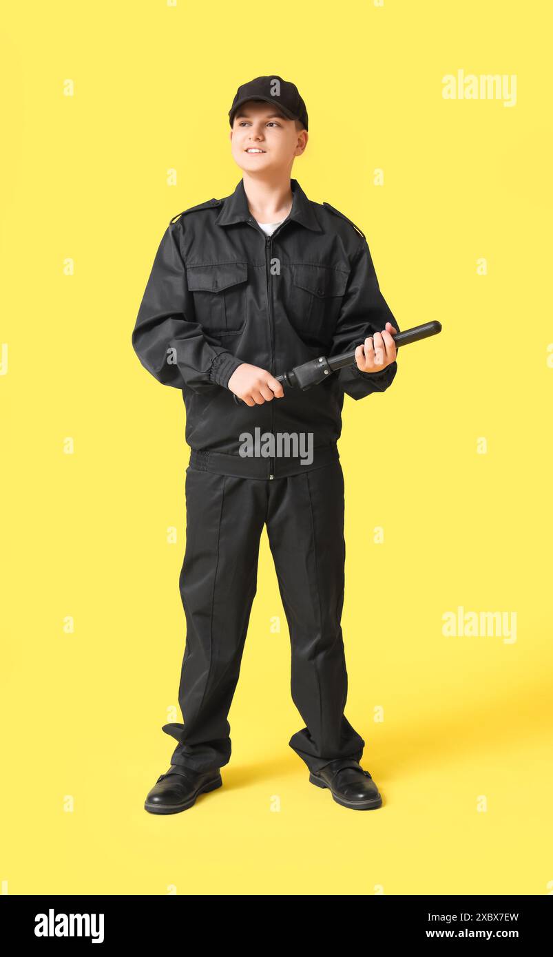 Teenage police officer with baton on yellow background Stock Photo - Alamy