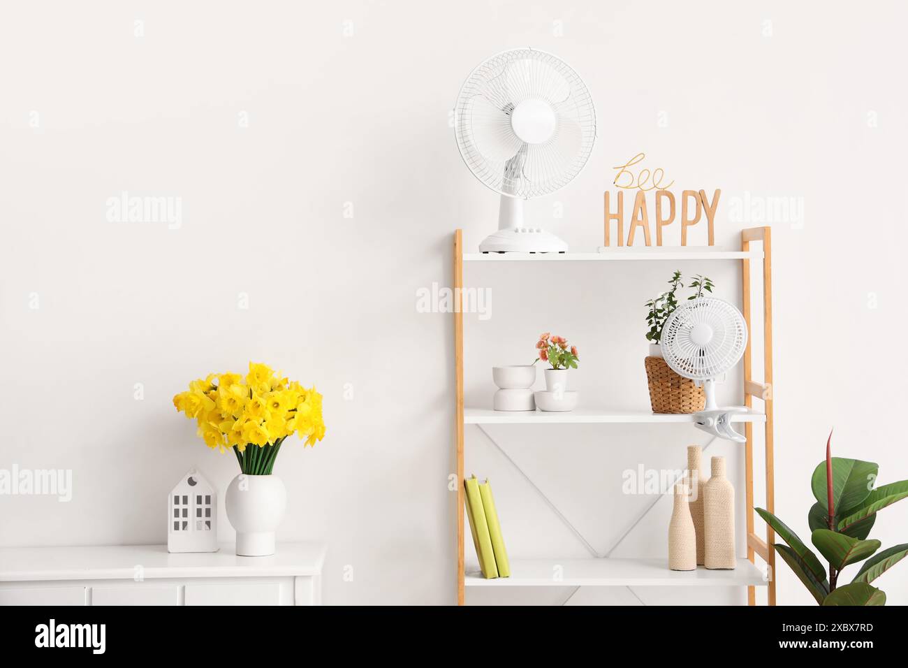 Modern electric fans with beautiful daffodils on shelving unit at home ...