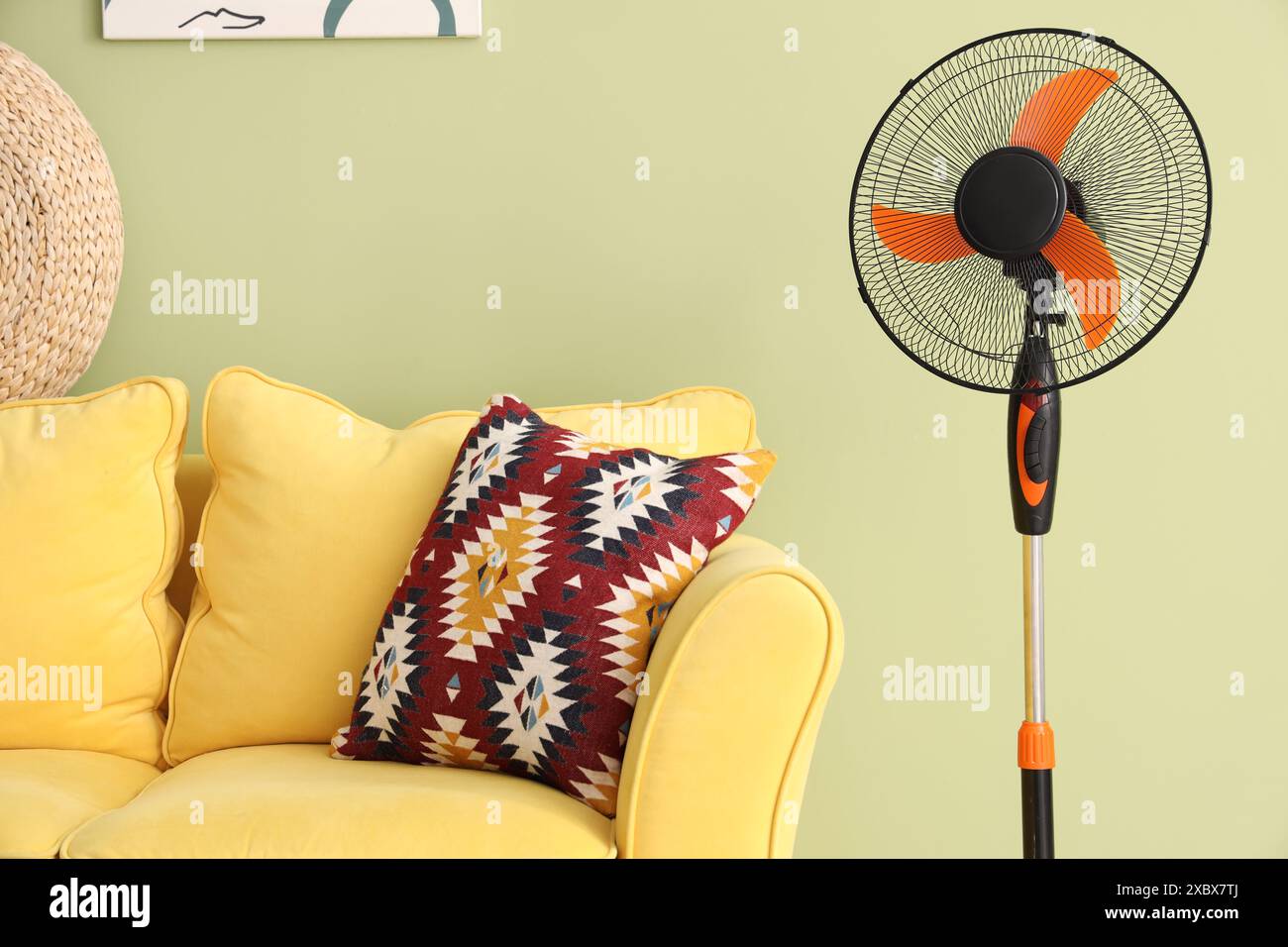 Modern electric fan and yellow sofa near green wall Stock Photo - Alamy