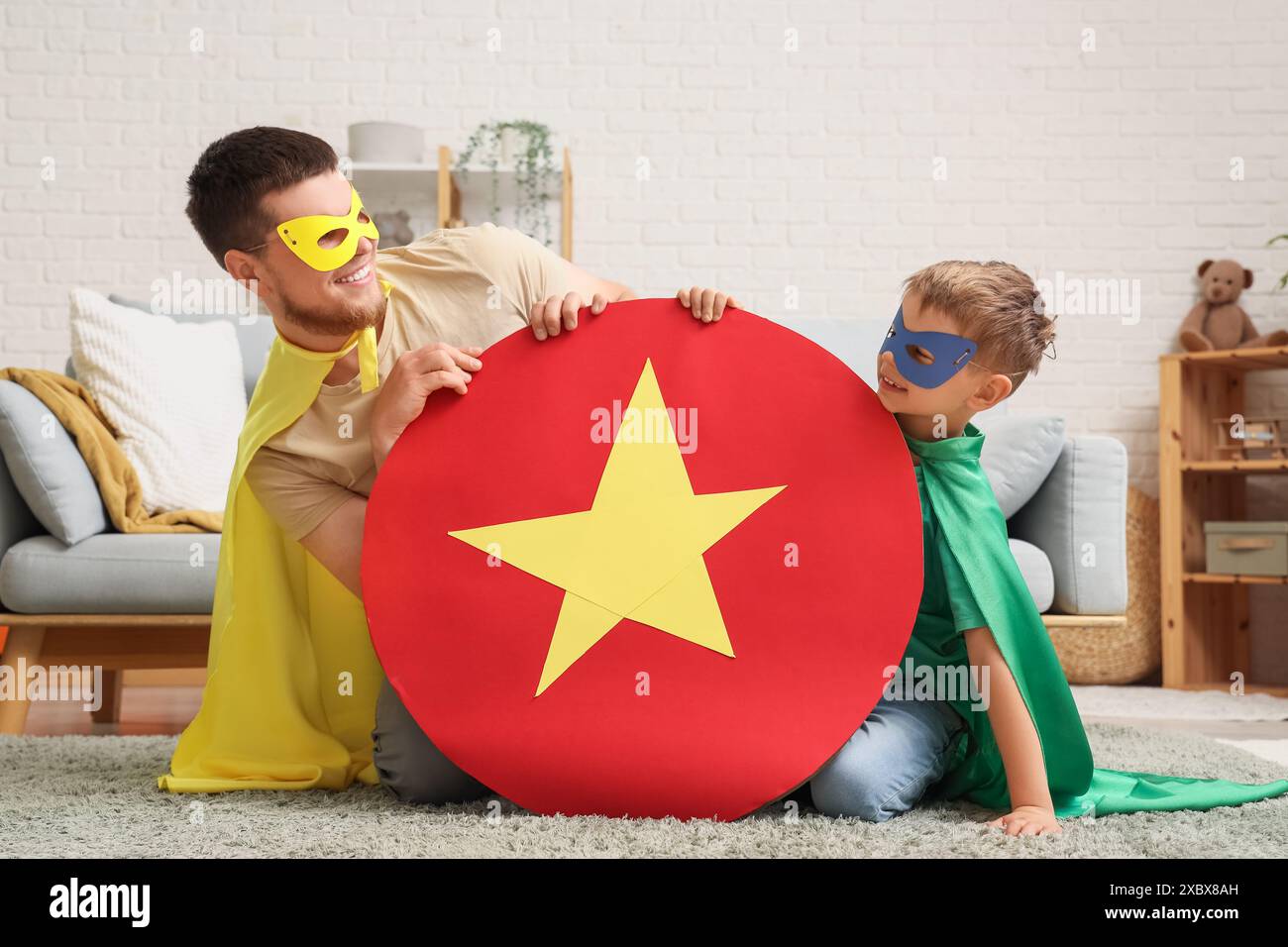 Little boy and his father in superhero costumes with paper shield at ...