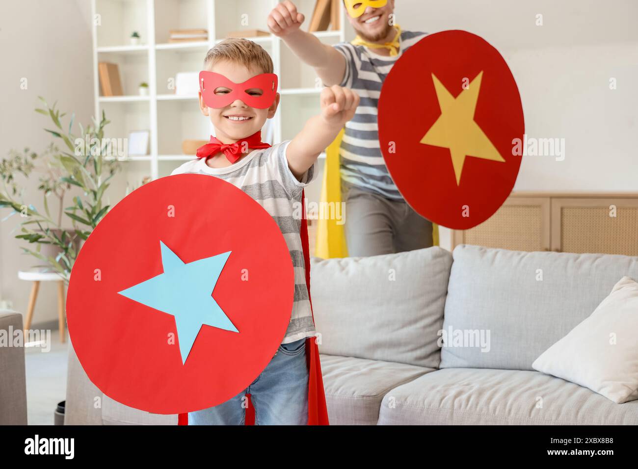 Little boy and his father in superhero costumes with paper shields at ...