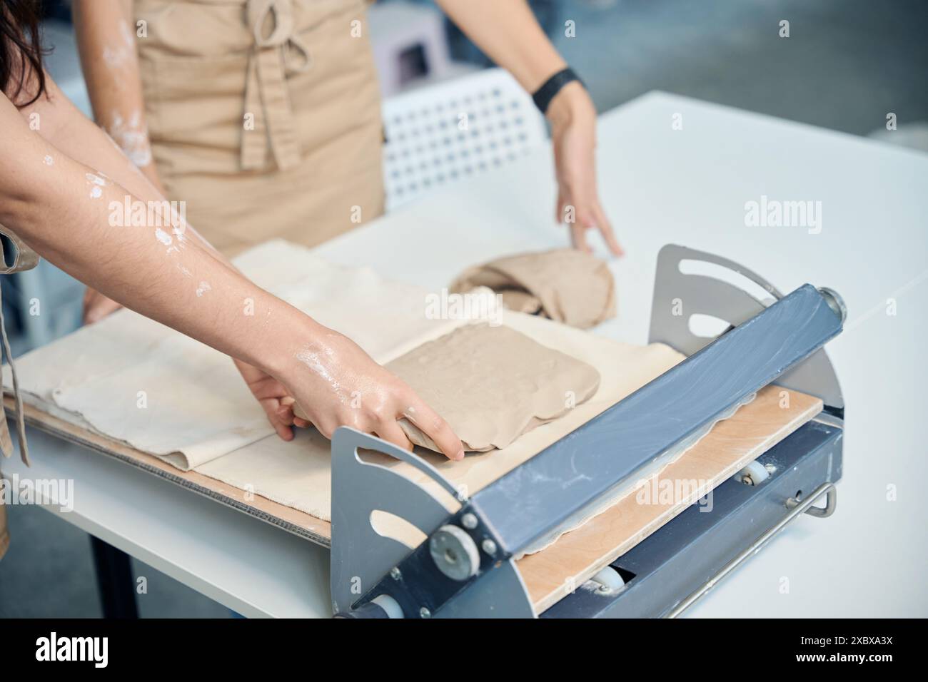 Female working potter rolling out clay slabs in her pottery studio ...