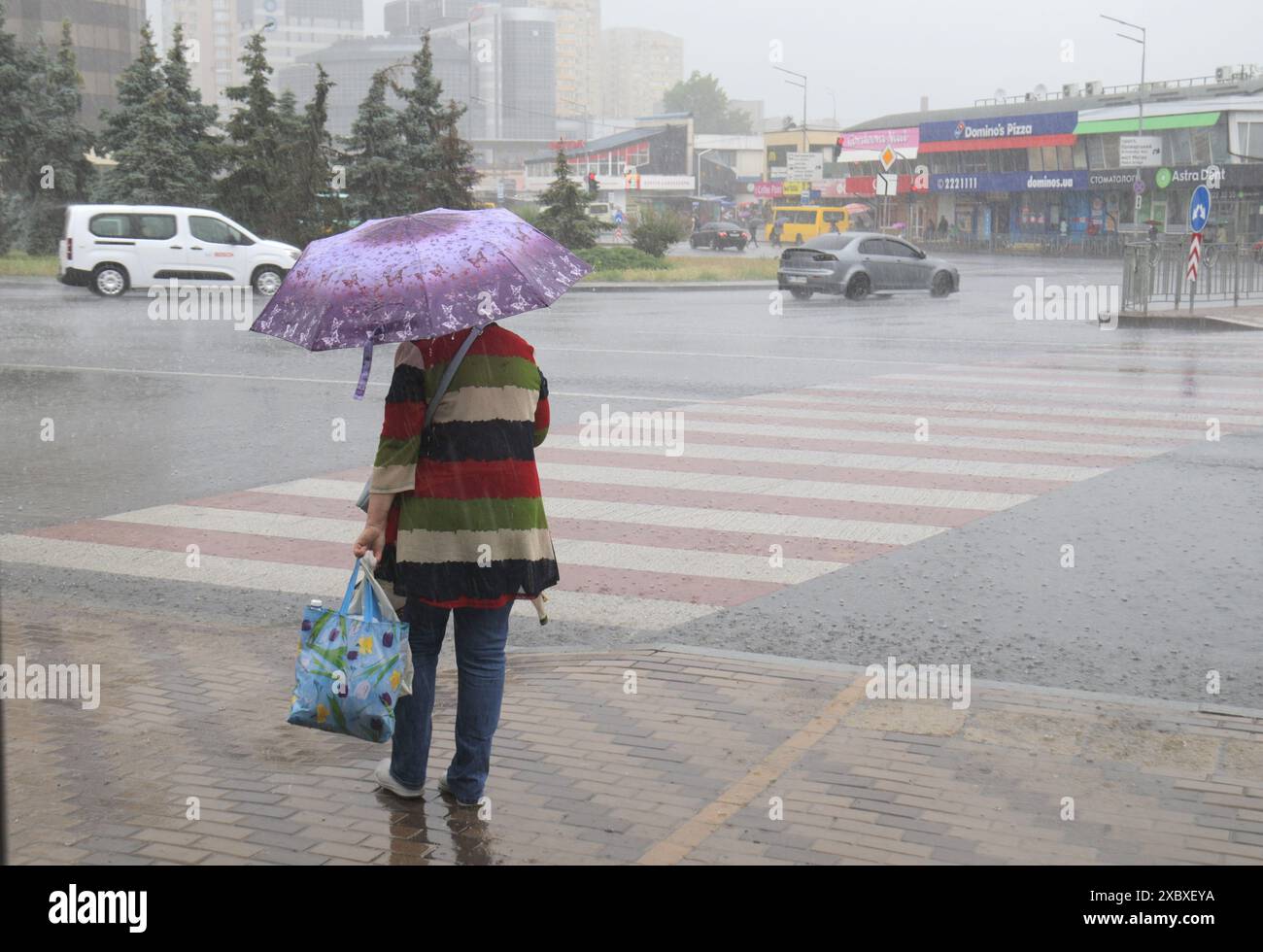 KYIV, UKRAINE - JUNE 12, 2024 - A woman walks under an umbrella during ...