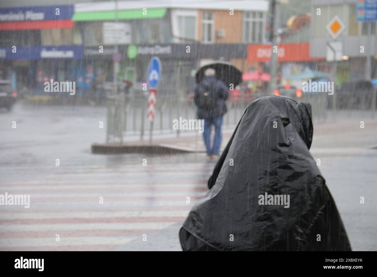 KYIV, UKRAINE - JUNE 12, 2024 - A woman covers her head with a jacket ...