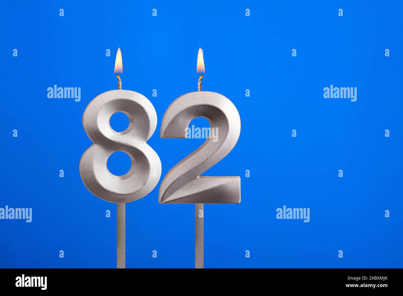 Birthday number 82 - Candle lit on blue background Stock Photo - Alamy