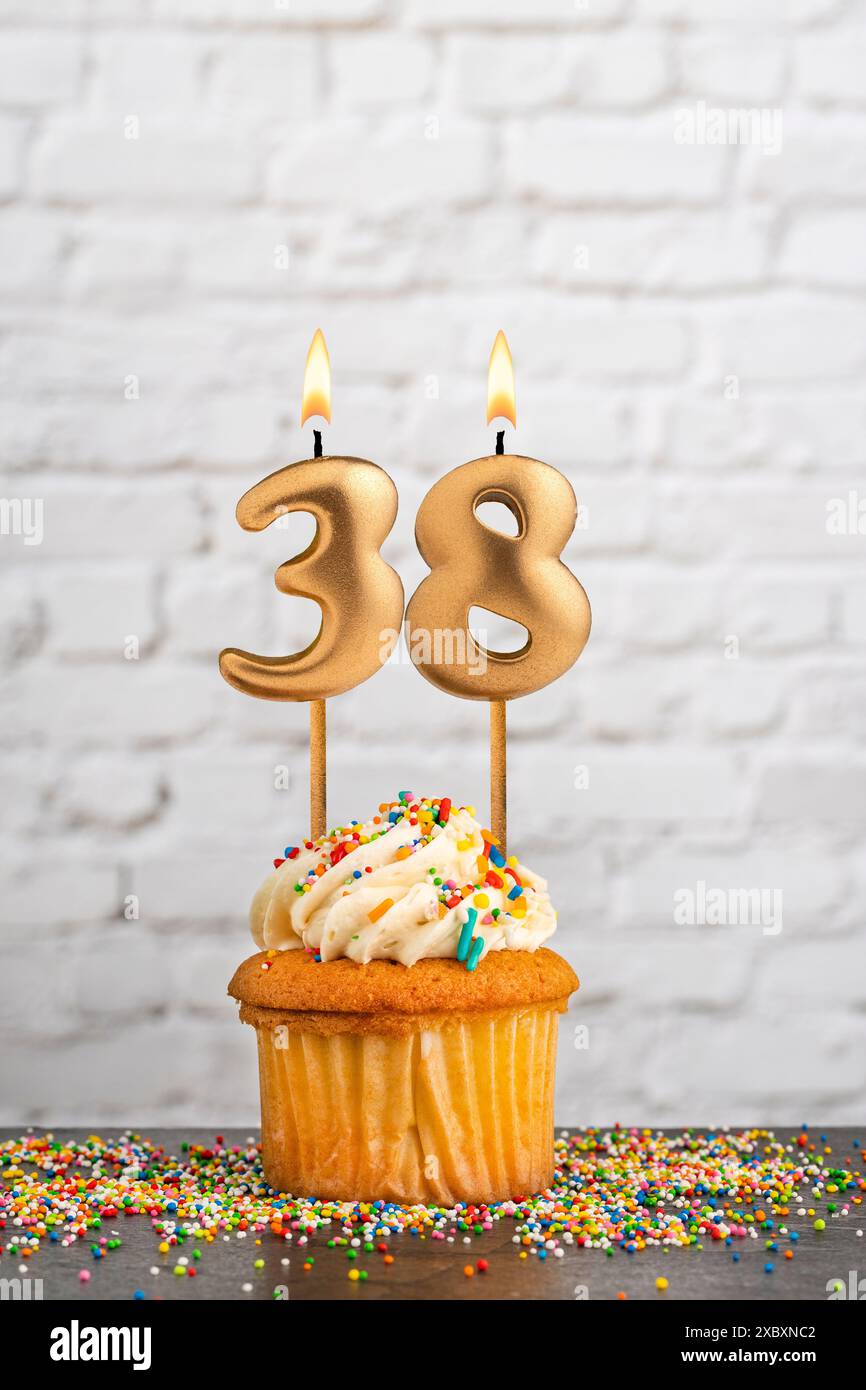 Cupcake with number 38 birthday candle - White block wall background ...