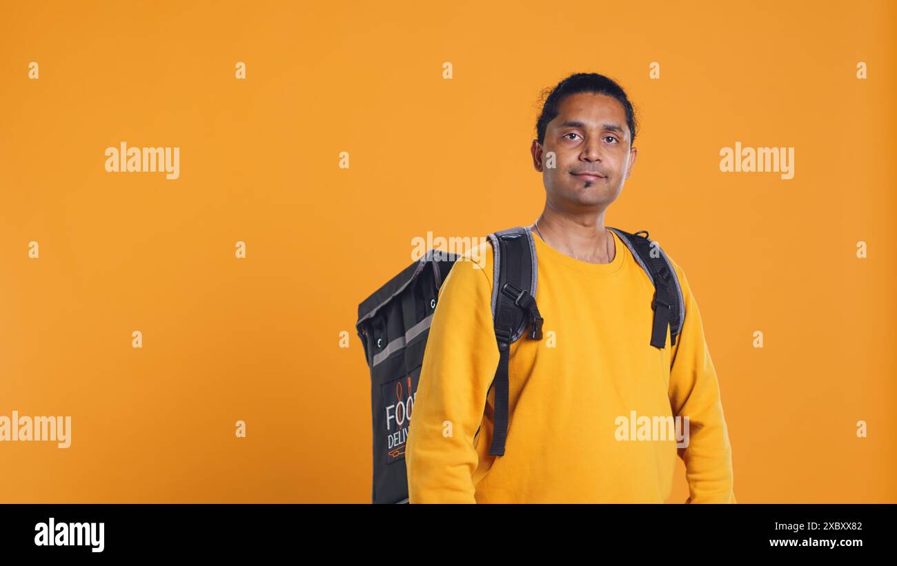 Portrait of confident indian man holding thermal backpack, crossing ...