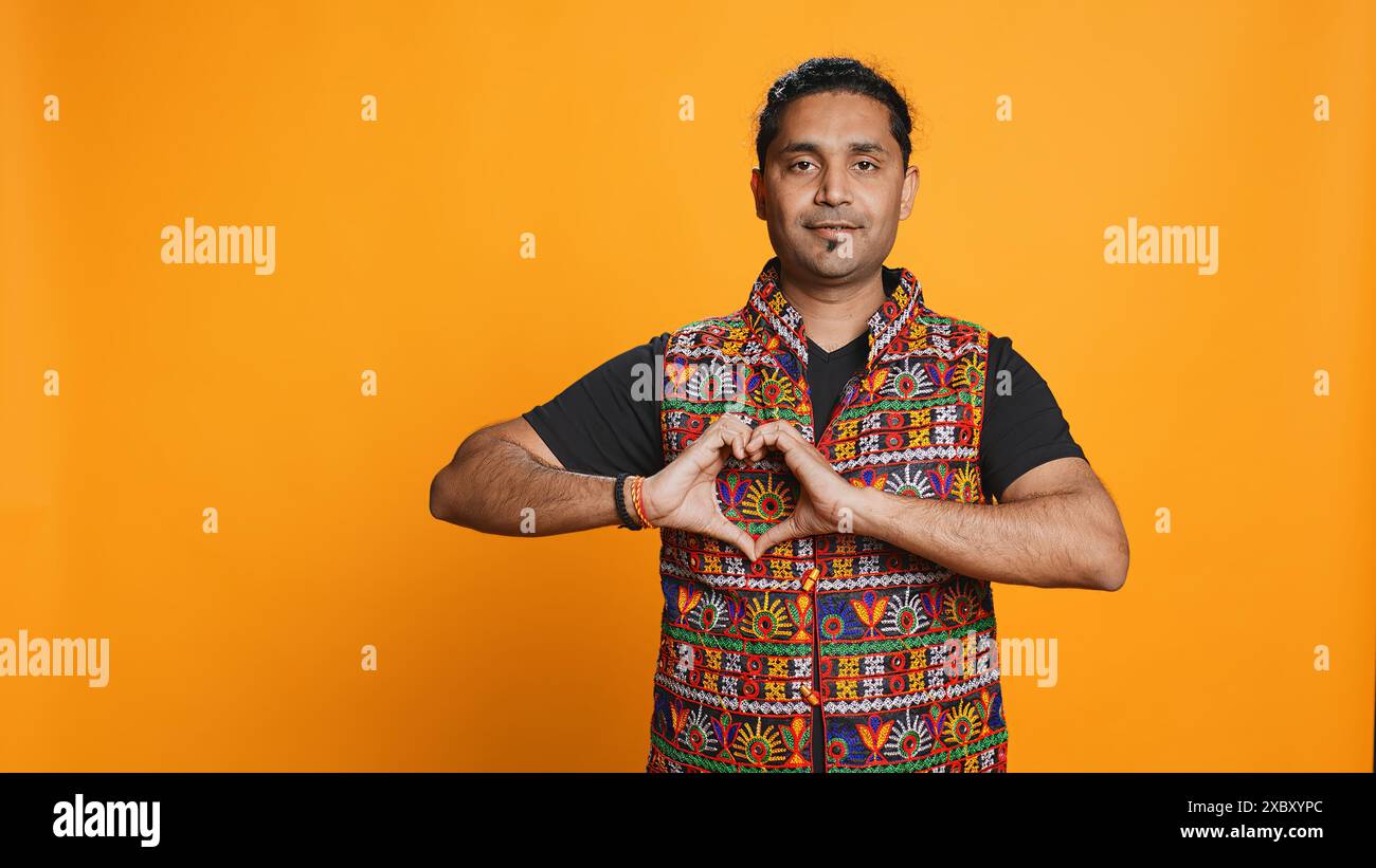 Portrait of smiling loving man doing heart symbol shape gesture with ...