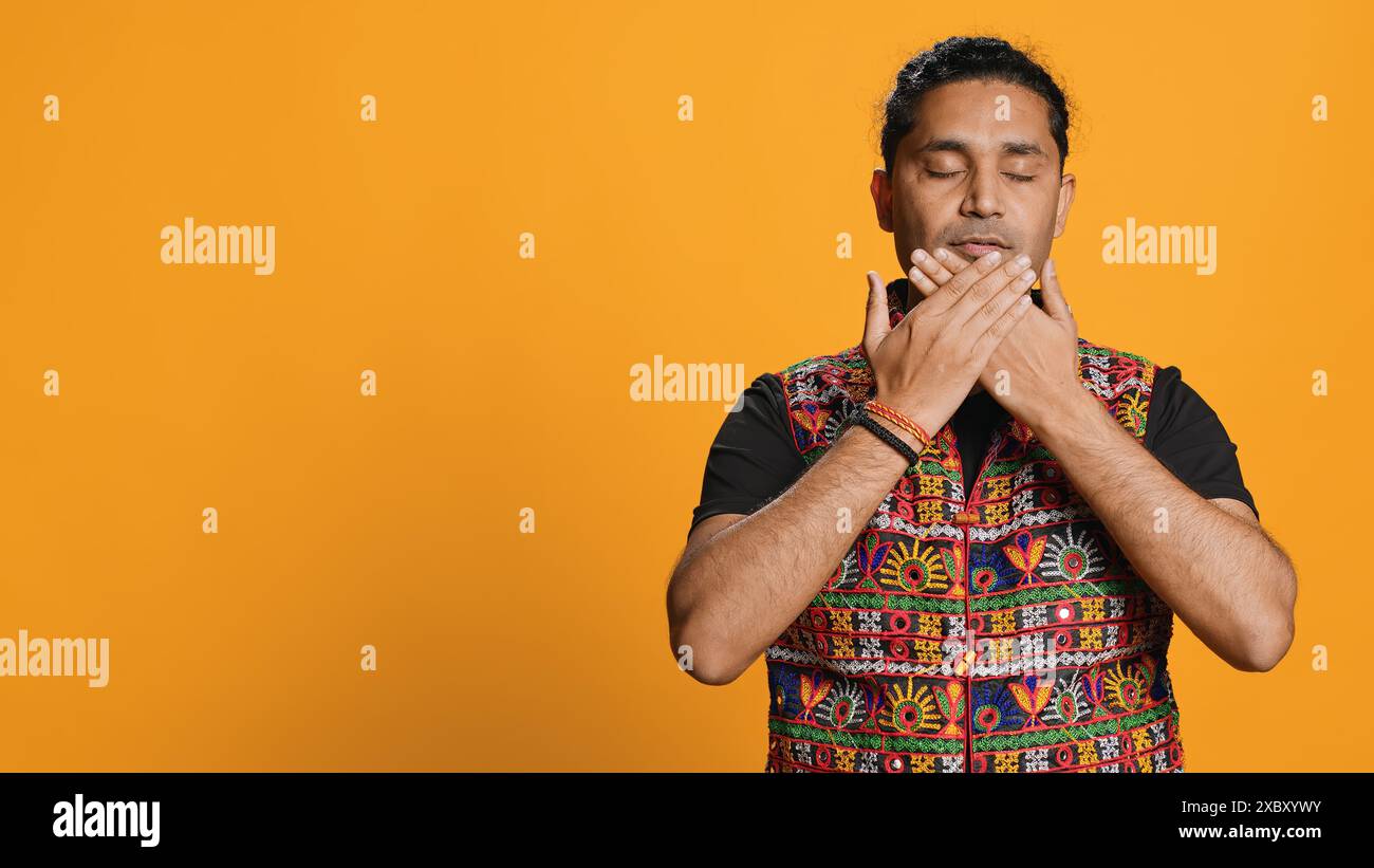 Man wearing traditional indian clothing covering eyes, ears and mouth ...