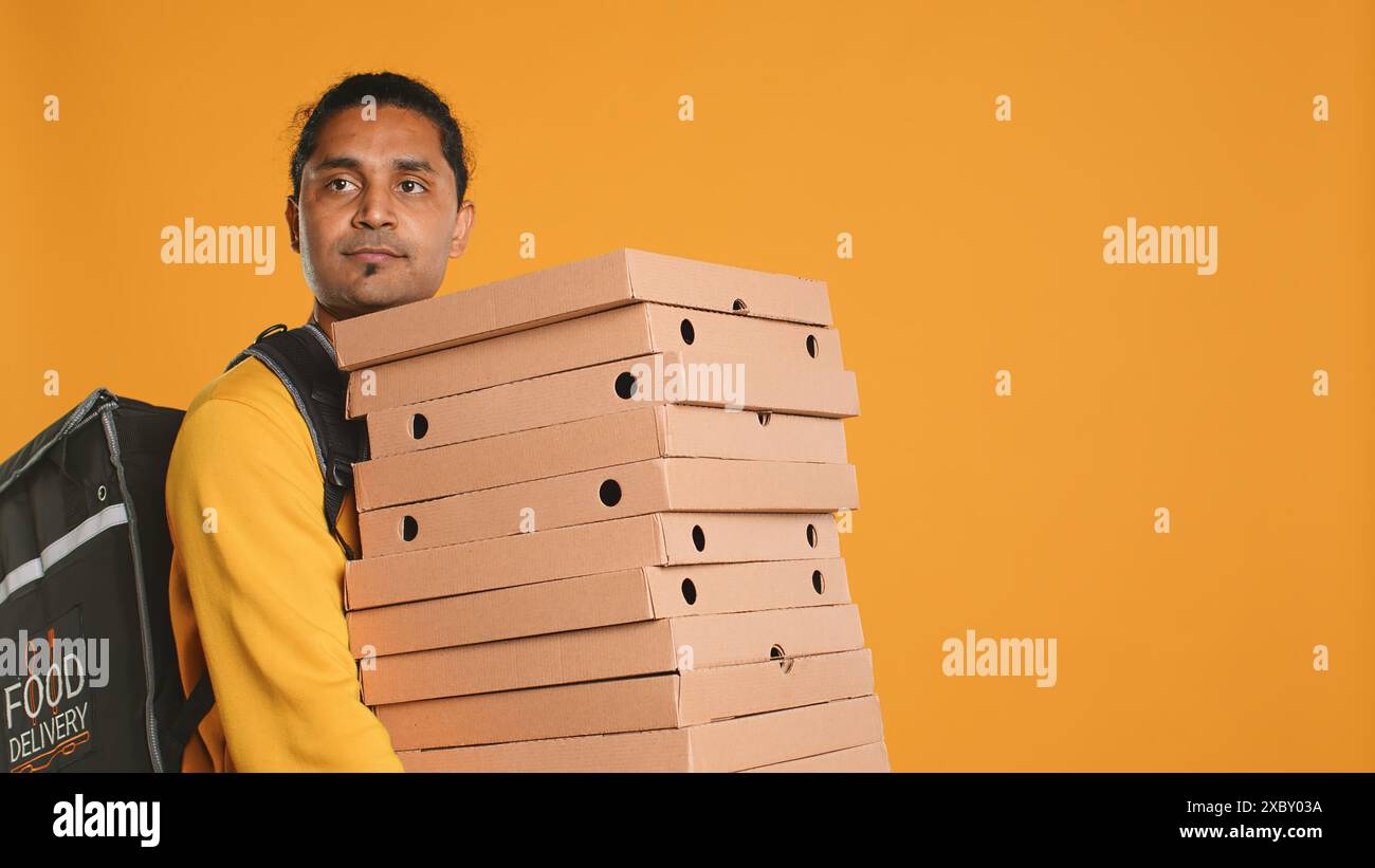 Indian pizza delivery worker carrying takeaway orders, wearing thermal ...