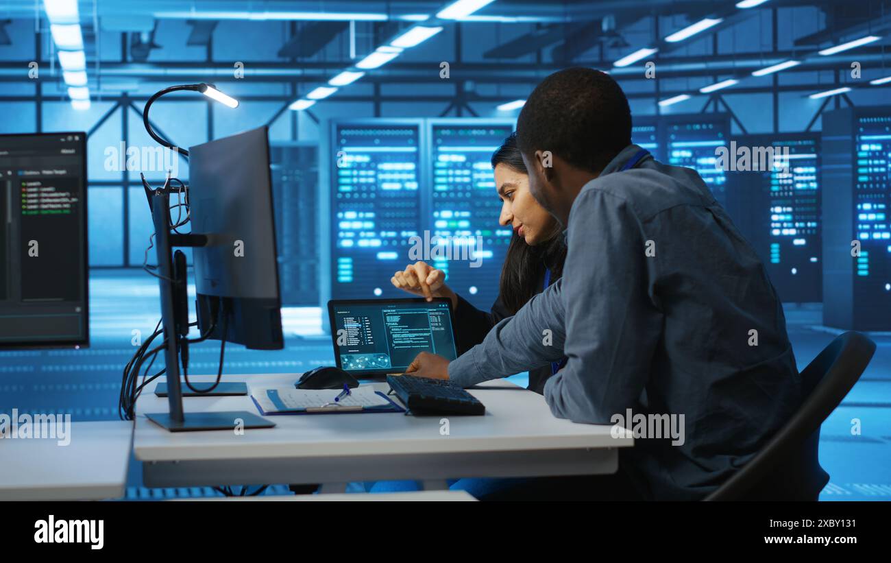 Multiethnic coworkers doing system analysis of server farm supercomputers using tablet. Diverse ...