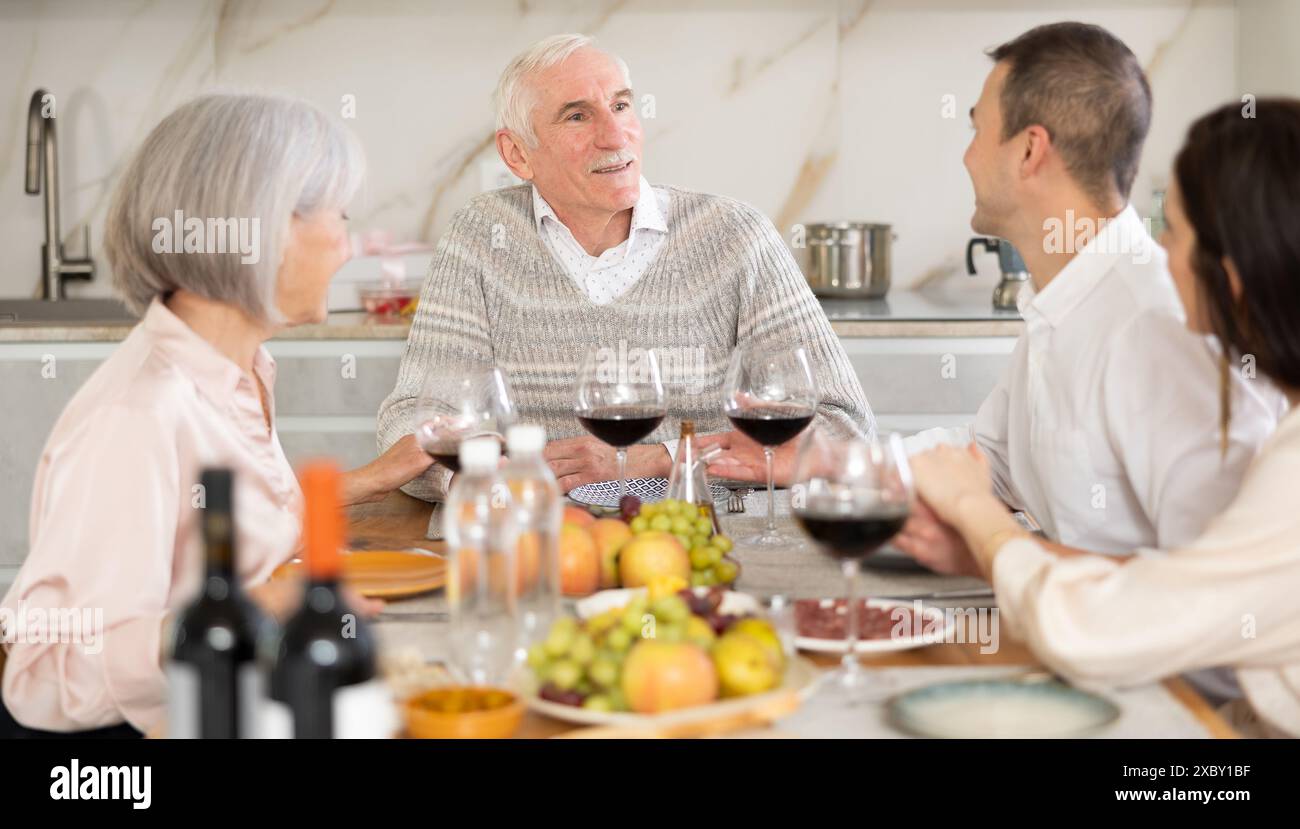 Aged man enjoying family dinner with wife, adult daughter and son-in-law Stock Photo - Alamy