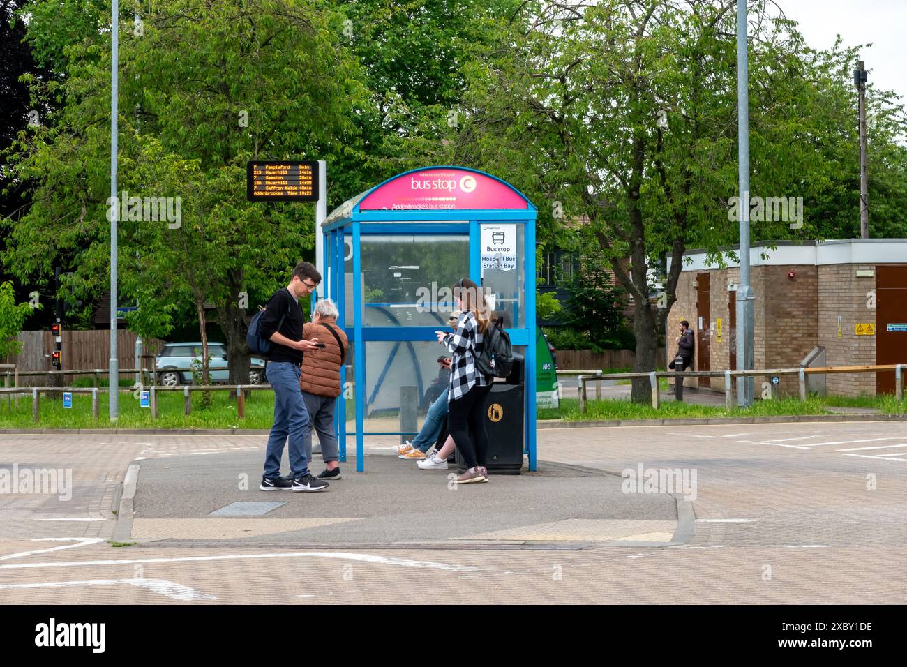 A bus stop bus shelter with digital sign and people waiting at ...