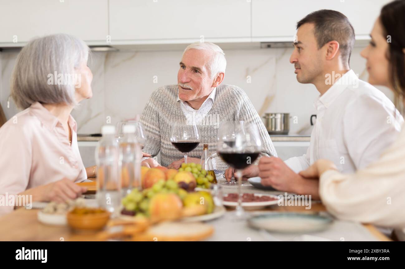 Elderly man enjoying dinner with wife, grown son and daughter-in-law Stock Photo - Alamy