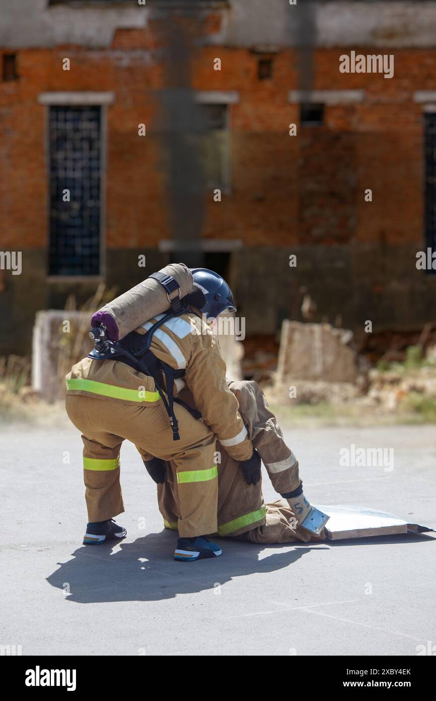 Fireman in uniform is dragging a mannequin on training Stock Photo - Alamy