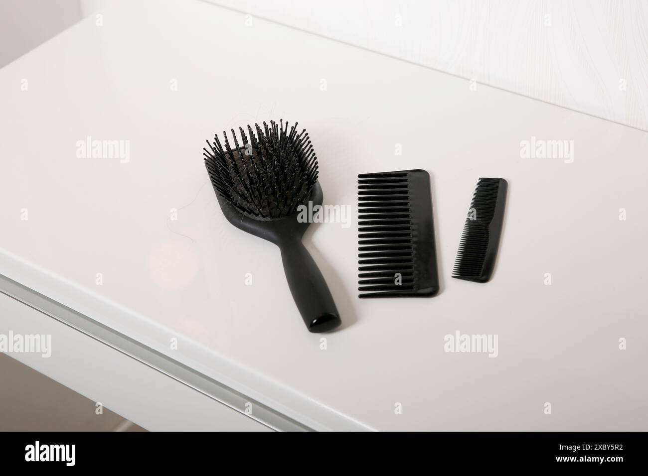 Used hair brush and combs with some hair on white table, head skin ...