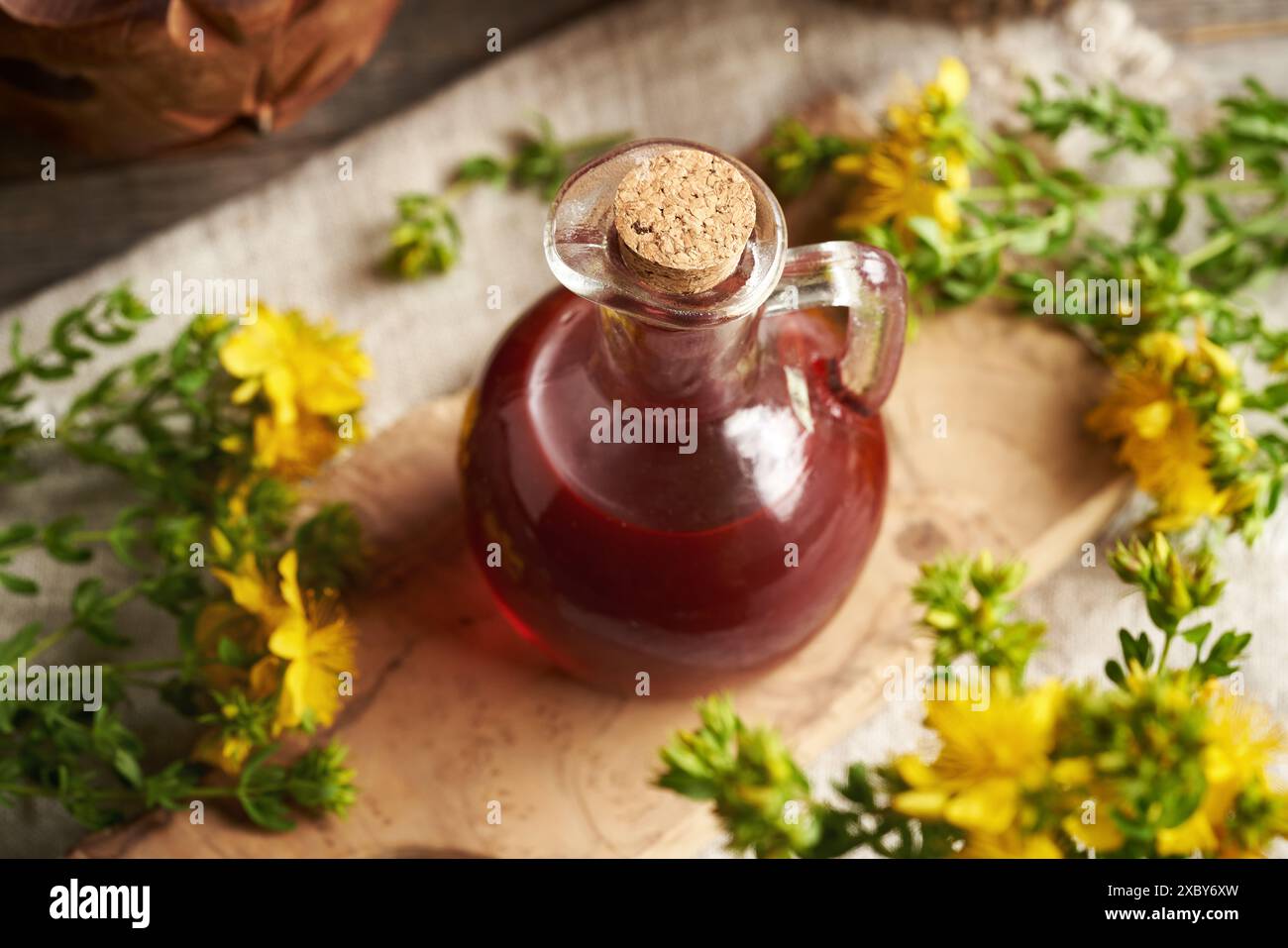 Red St. John's wort oil in a glass jar with fresh Hypericum flowers ...