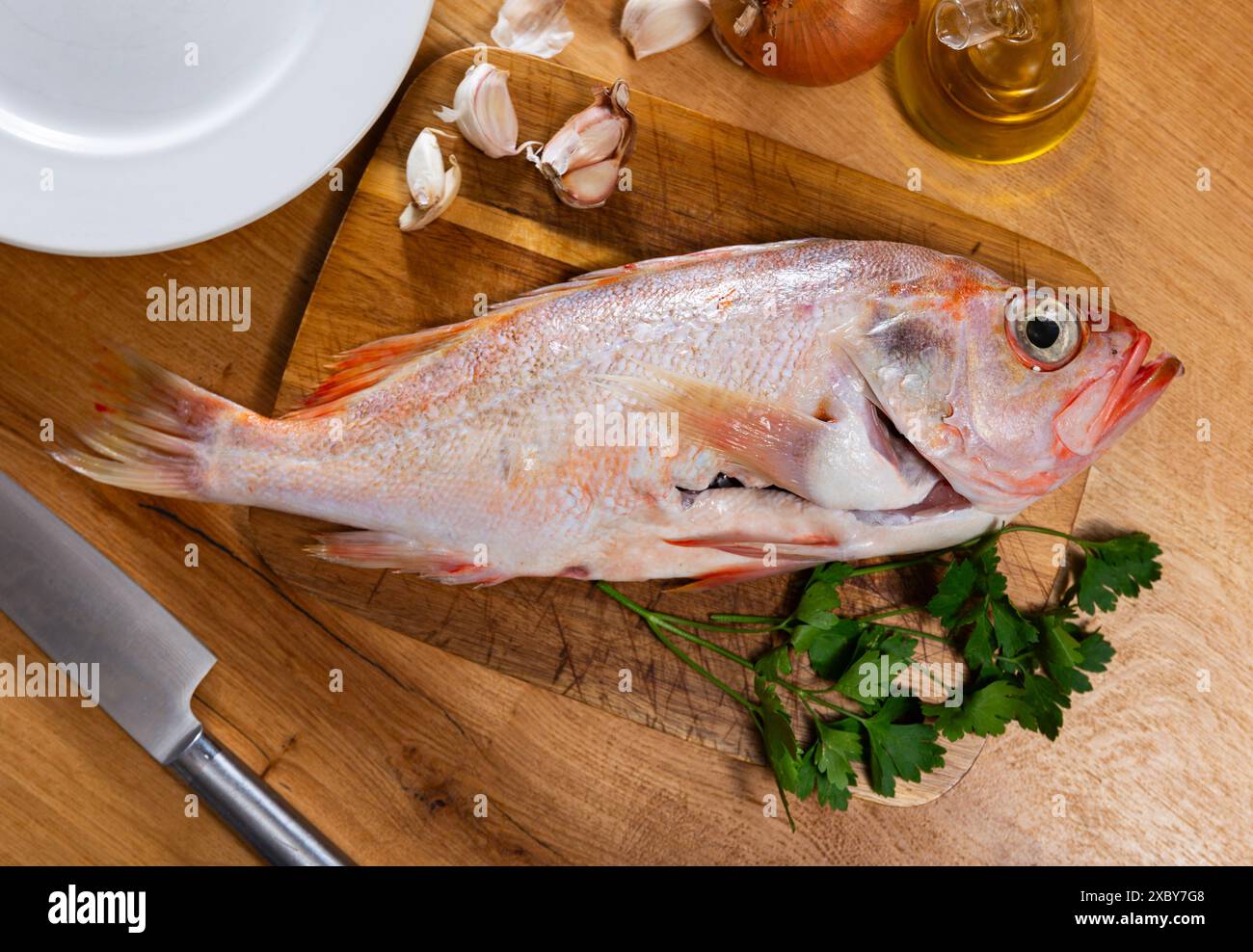 Raw whole red palometa fish with garlic and parsley on desk Stock Photo ...