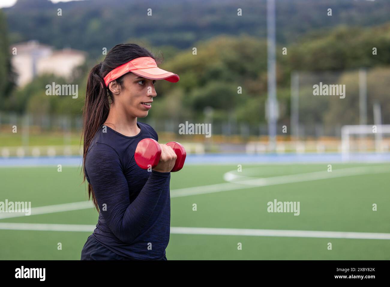 closeup female athlete wearing a cap lifts a dumbbell to train her ...