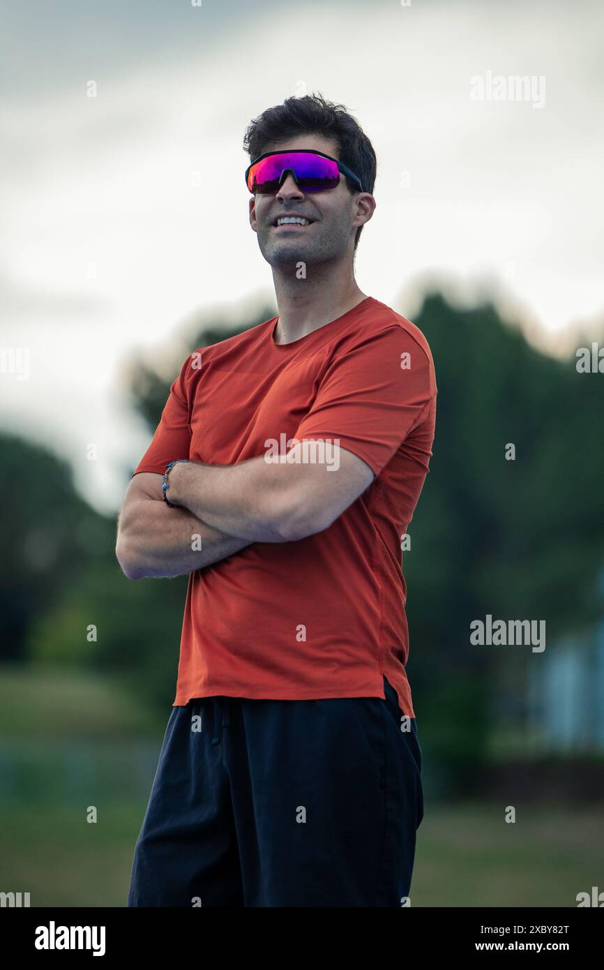 vertical sportsman wearing sunglasses poses outdoors with his arms crossed, displaying ...