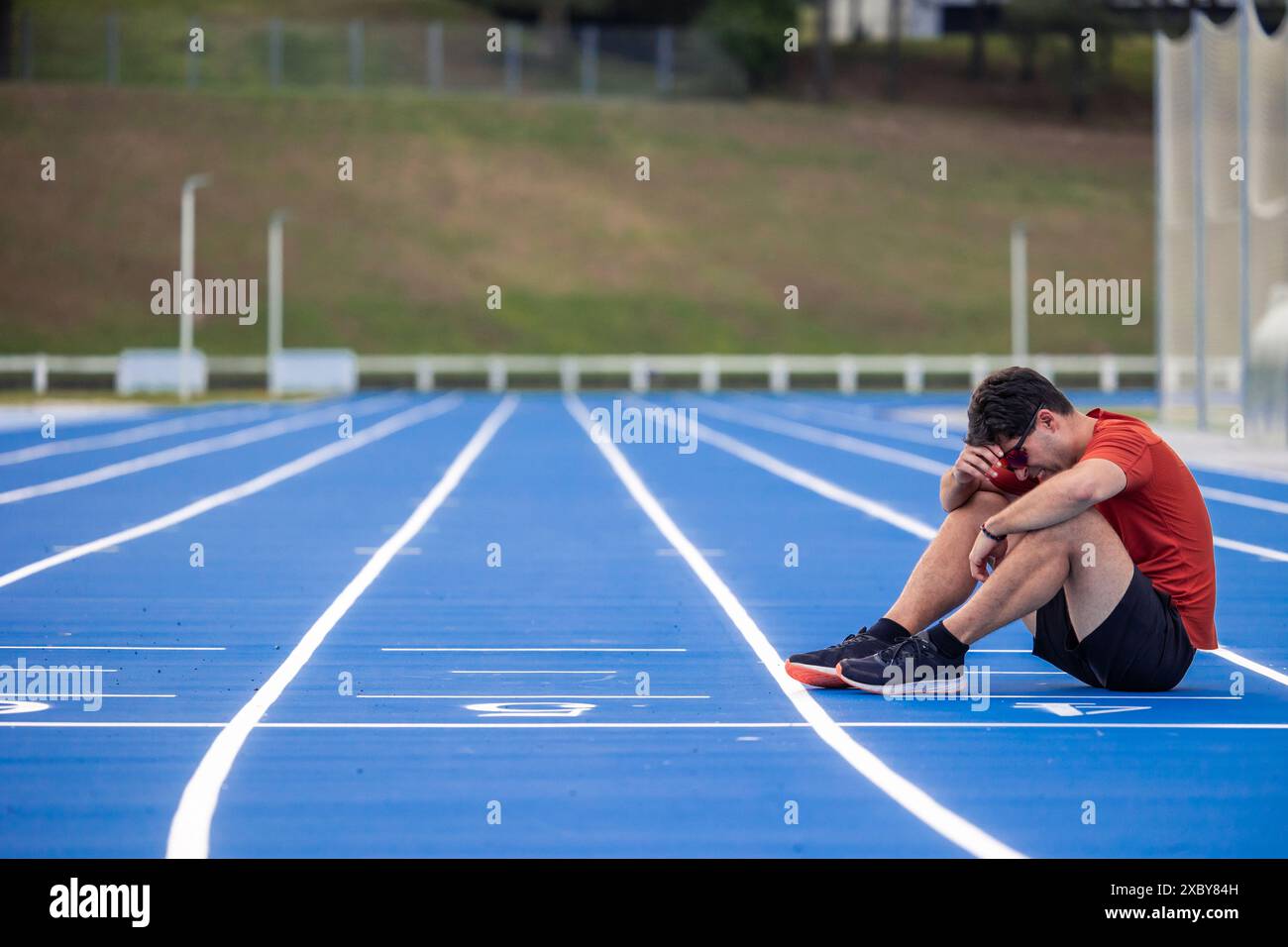 copyspace exhausted runner, his face showing signs of suffering, sits ...