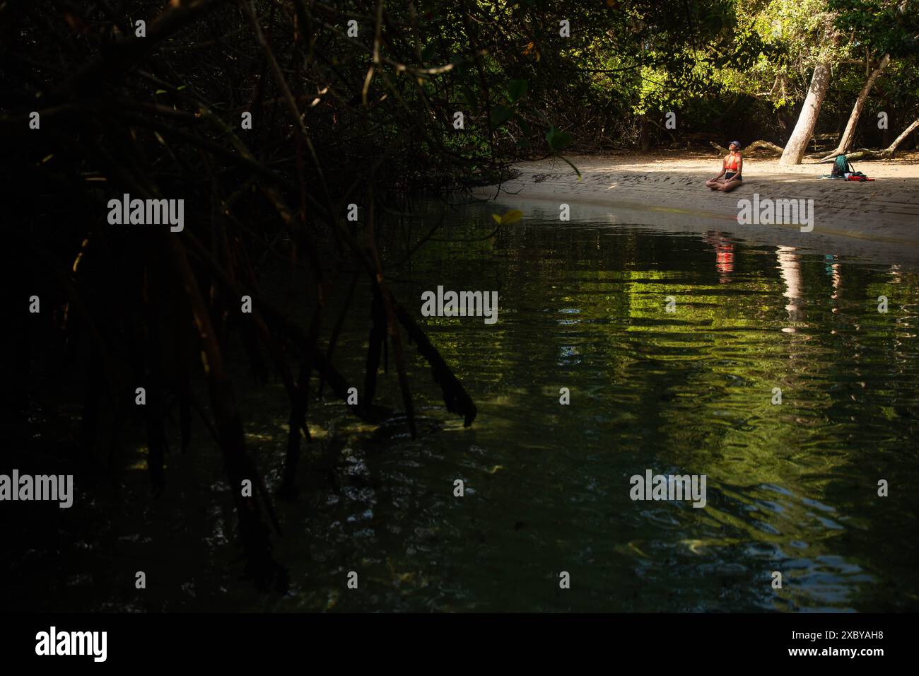 A woman meditates on a secluded, hidden mangove beach on Isla Isabela ...