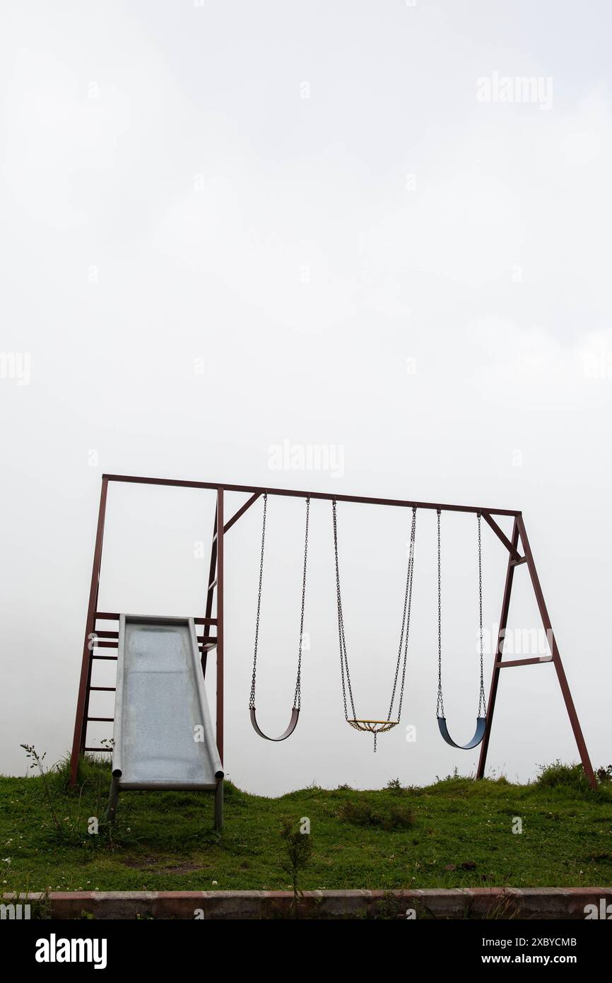A playground with swings and a slide in a misty background creating a ...
