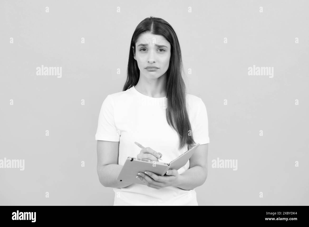Sad tired woman isolated over yellow background writing notes in ...