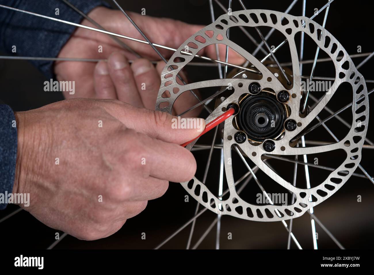 Mechanic mount disc brake rotor on bicycle wheel in bike workshop ...