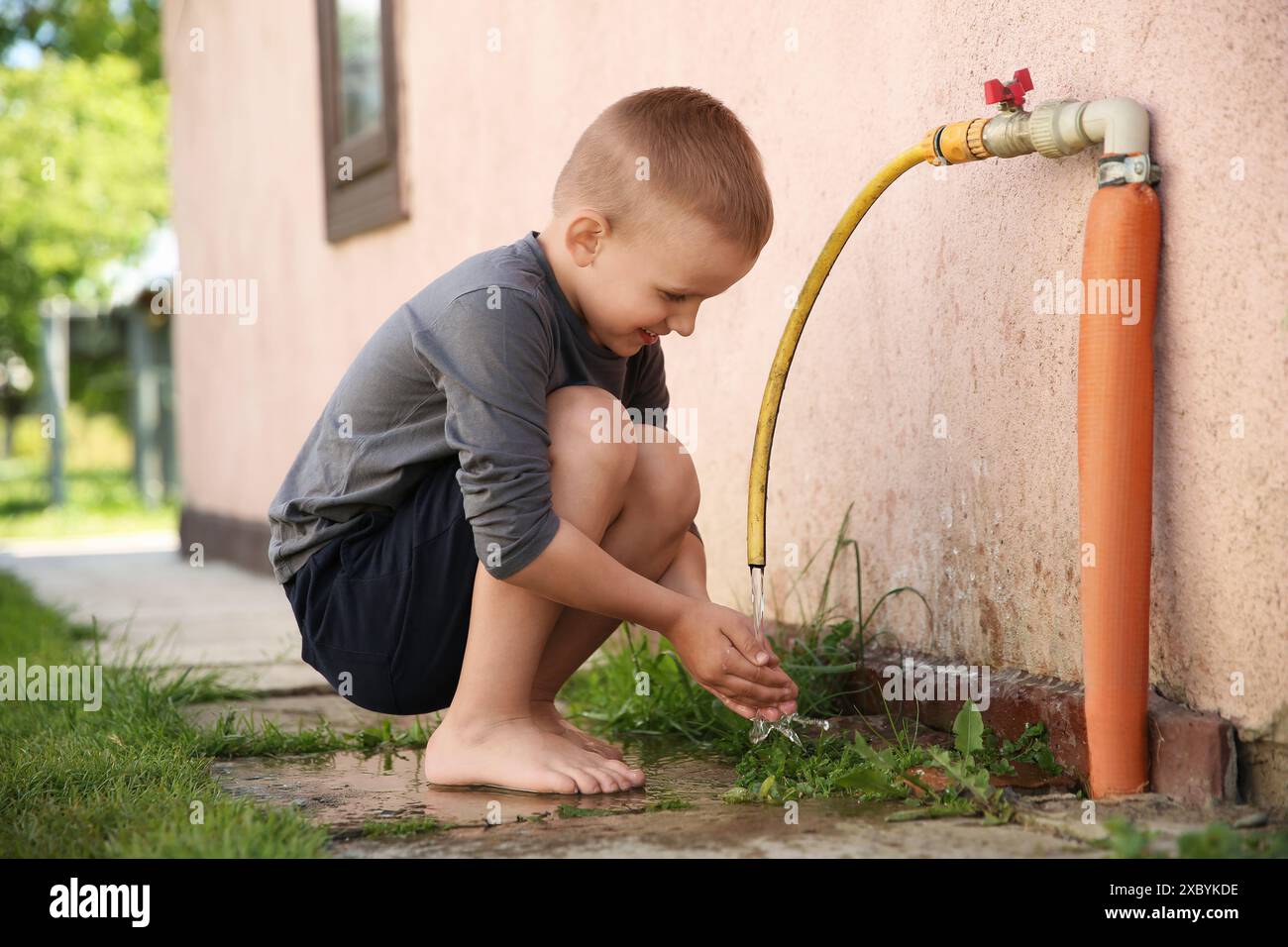 Water scarcity. Cute little boy drawing water with hands from tap ...