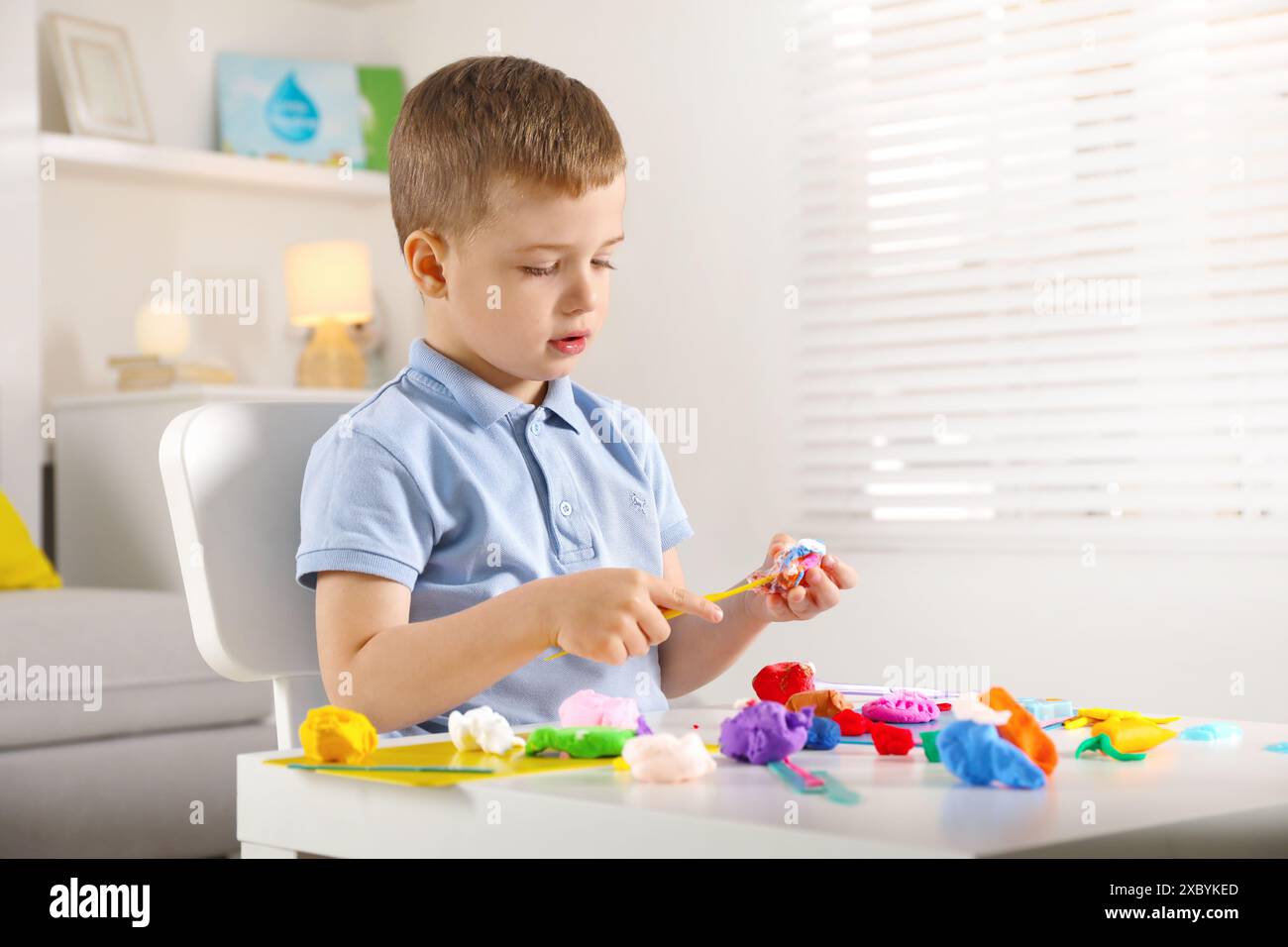 Little boy sculpting with play dough at table indoors Stock Photo - Alamy