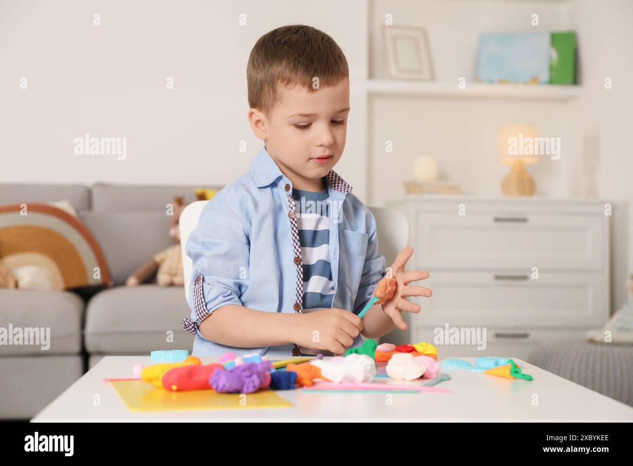 Little boy sculpting with play dough at table in kindergarten Stock ...