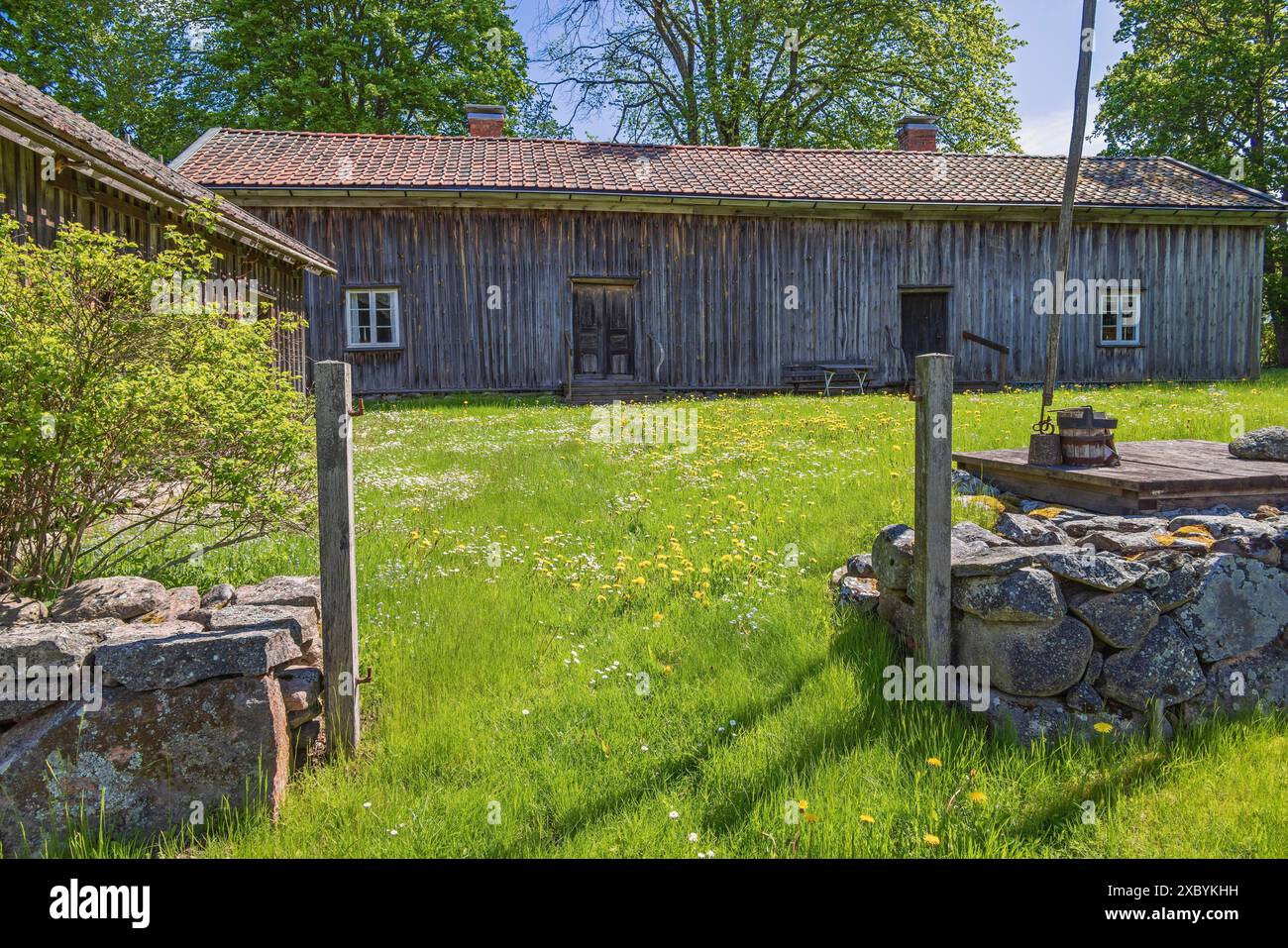 Rustic old farm with wooden house a water well and a gate by a stone ...