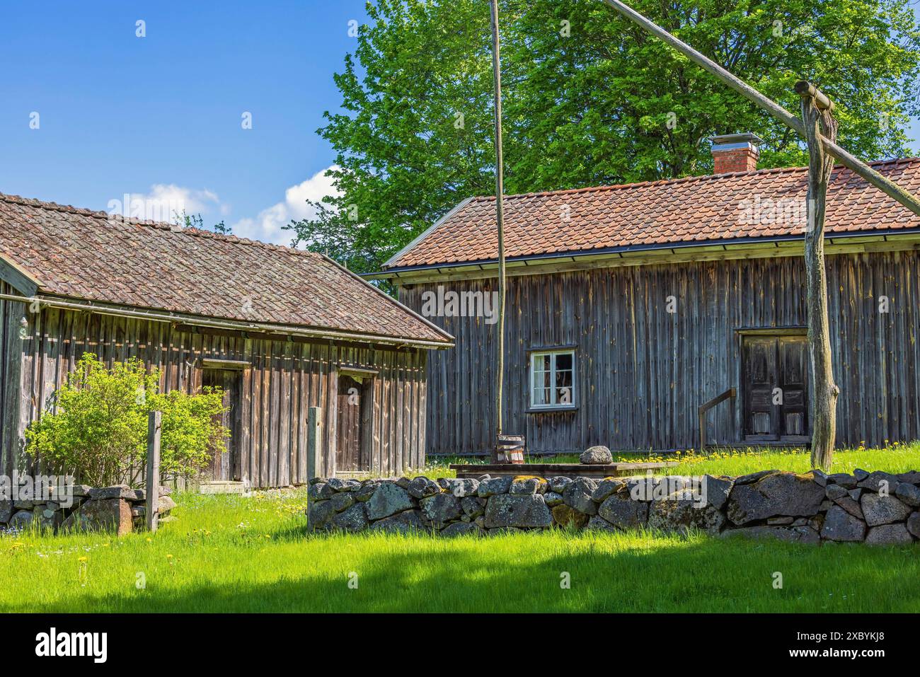 Rustic old farm with wooden house a water well and a stone wall in the ...